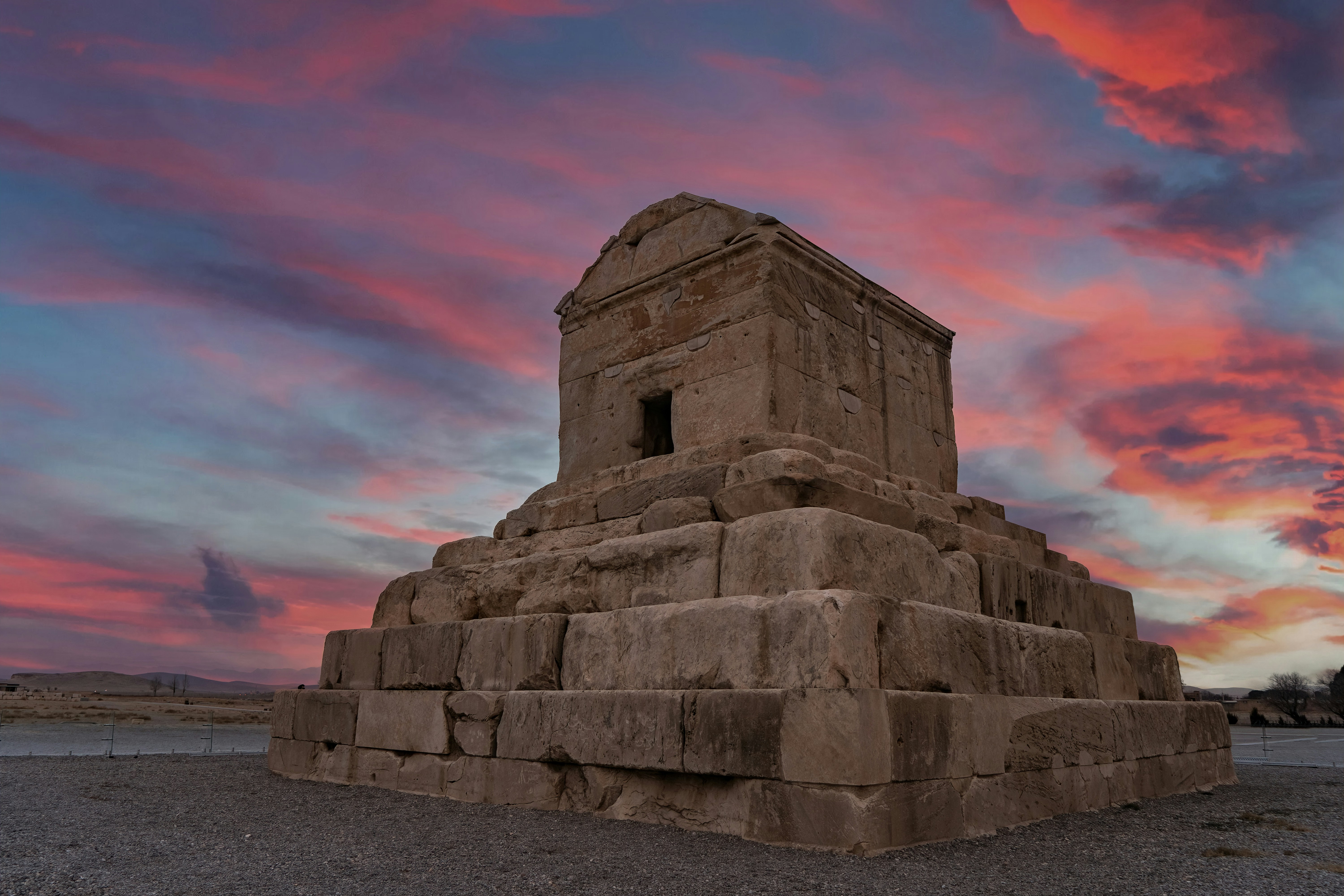 The tomb of Cyrus the Great is located in Pasargadae, which was the first capital city of his Achaemenid Empire and is now an archaeological site in the Fars Province of Iran. | Ancient stone tomb against a dramatic sunset sky