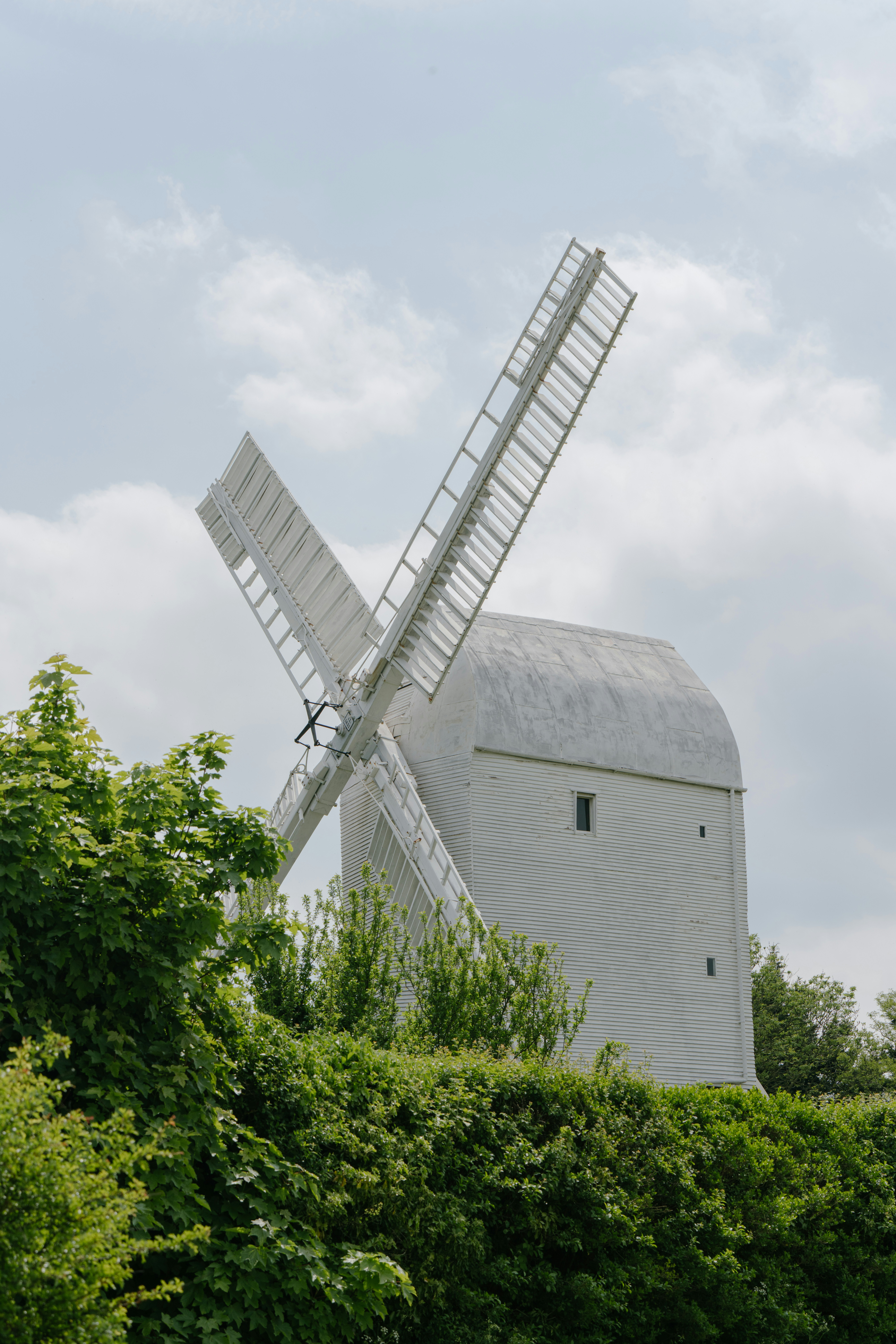 White windmill with large sails against cloudy sky