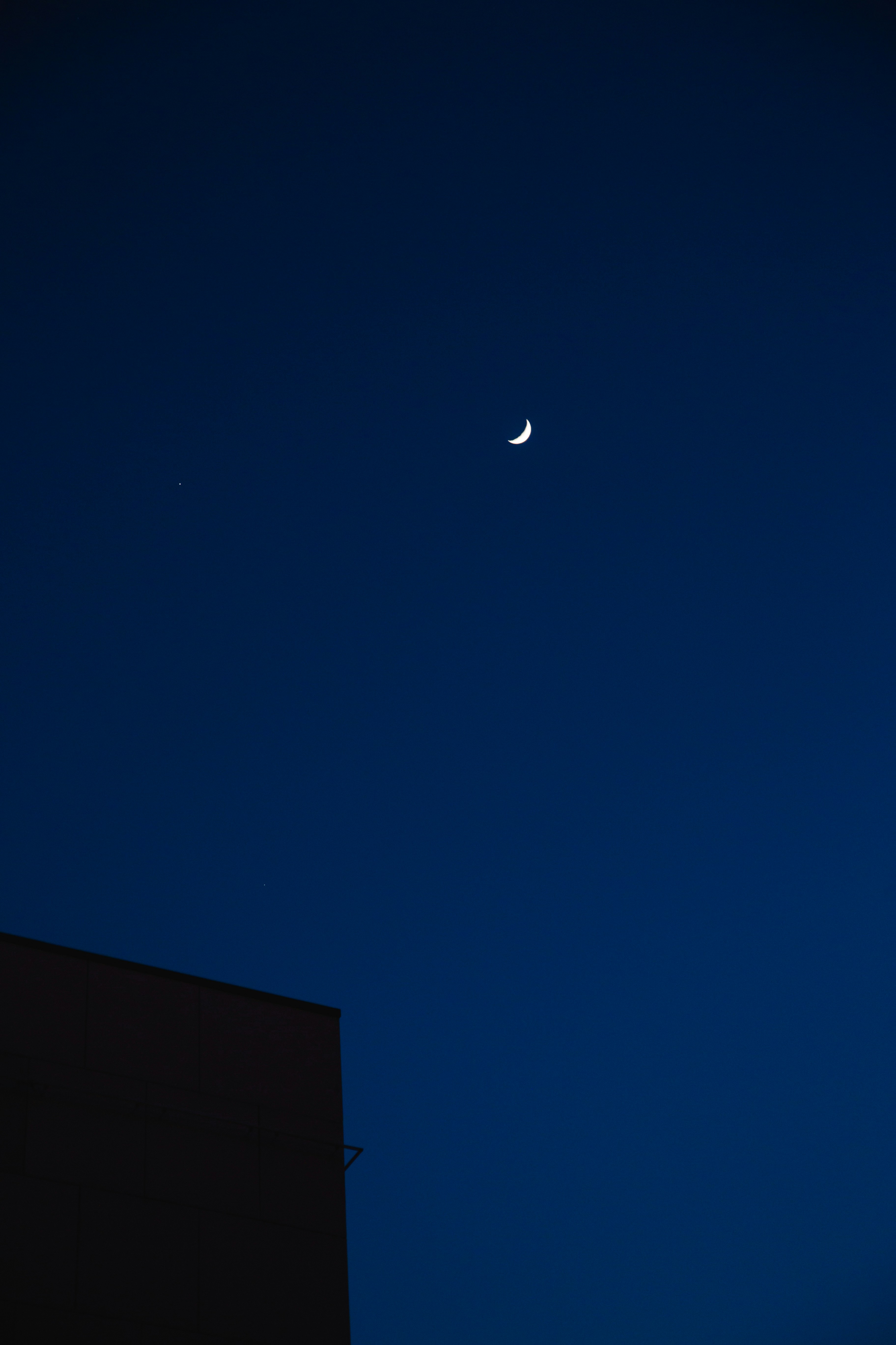Crescent moon and star in a dark blue sky.
