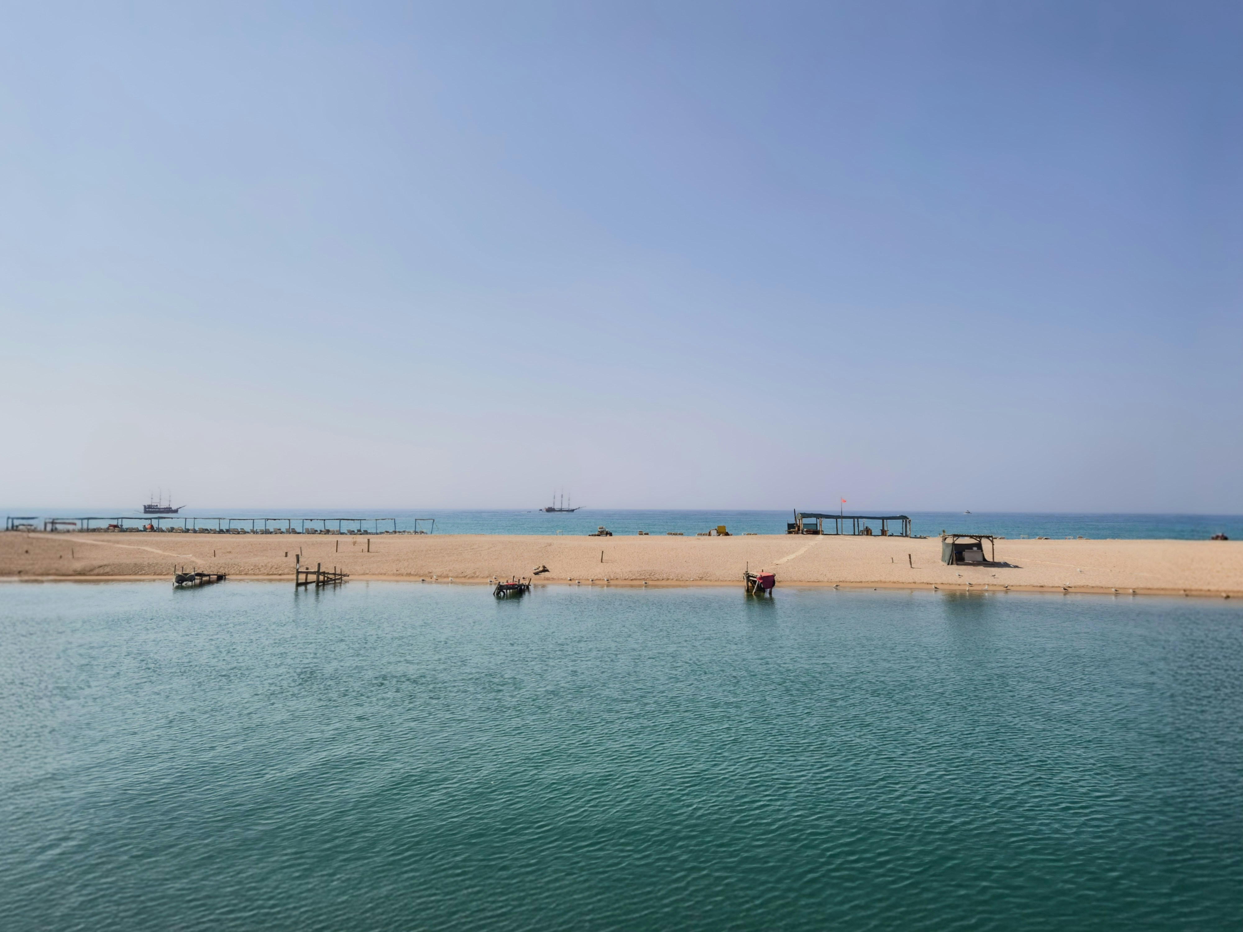 Boats on a sandy beach with calm blue water