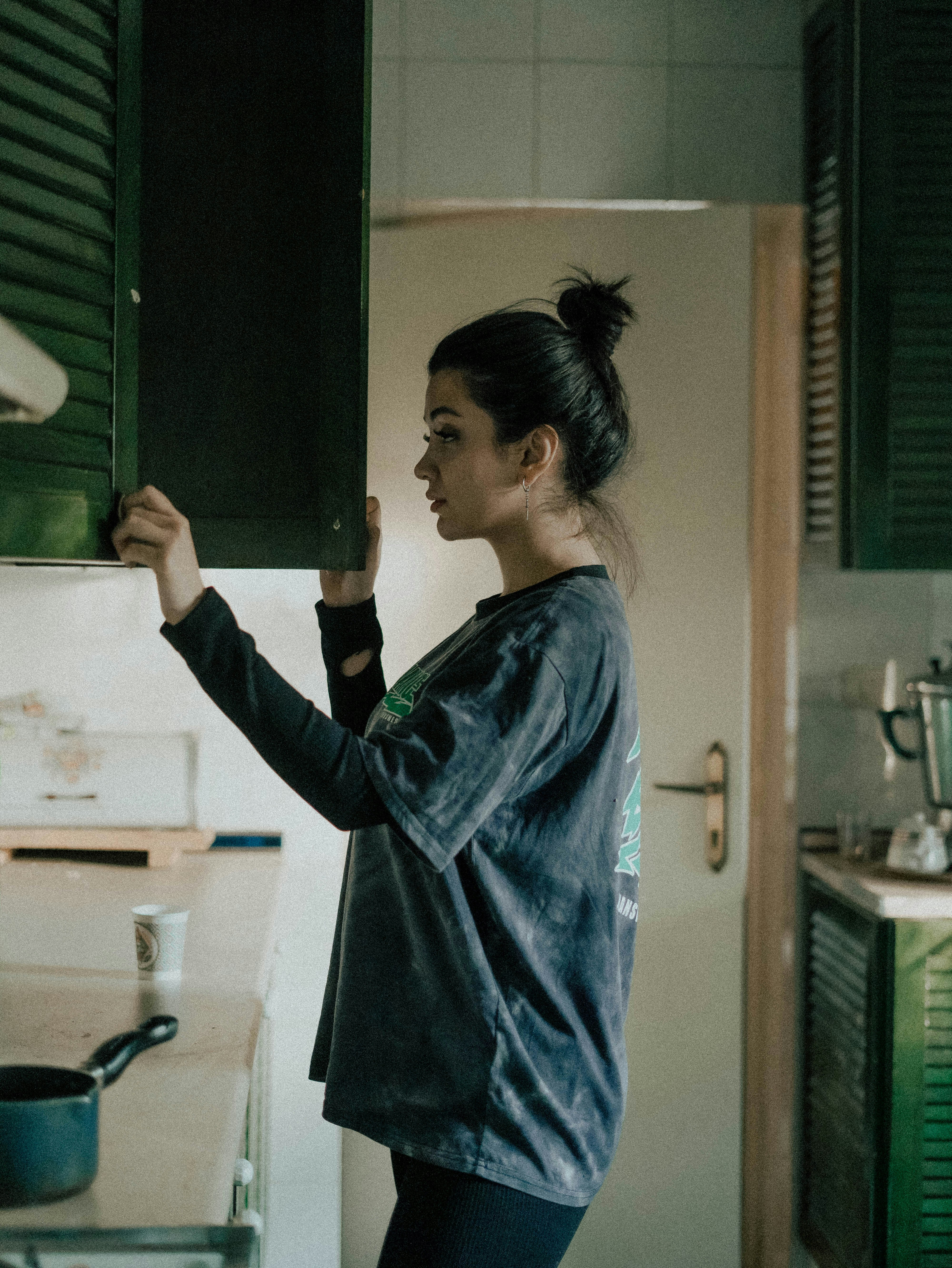 Young woman looking inside kitchen cabinet