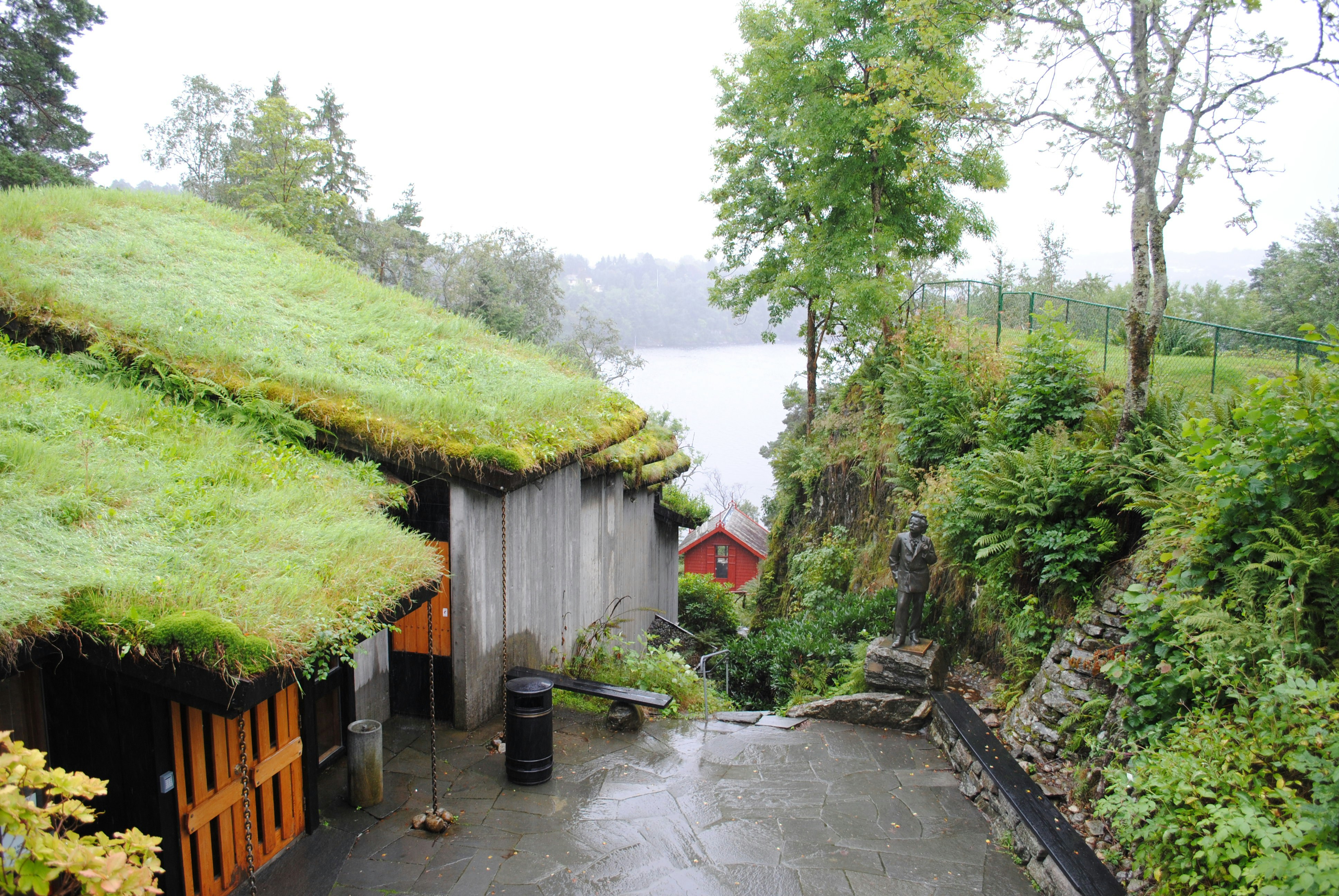 Wooden buildings with grass roofs near a body of water.