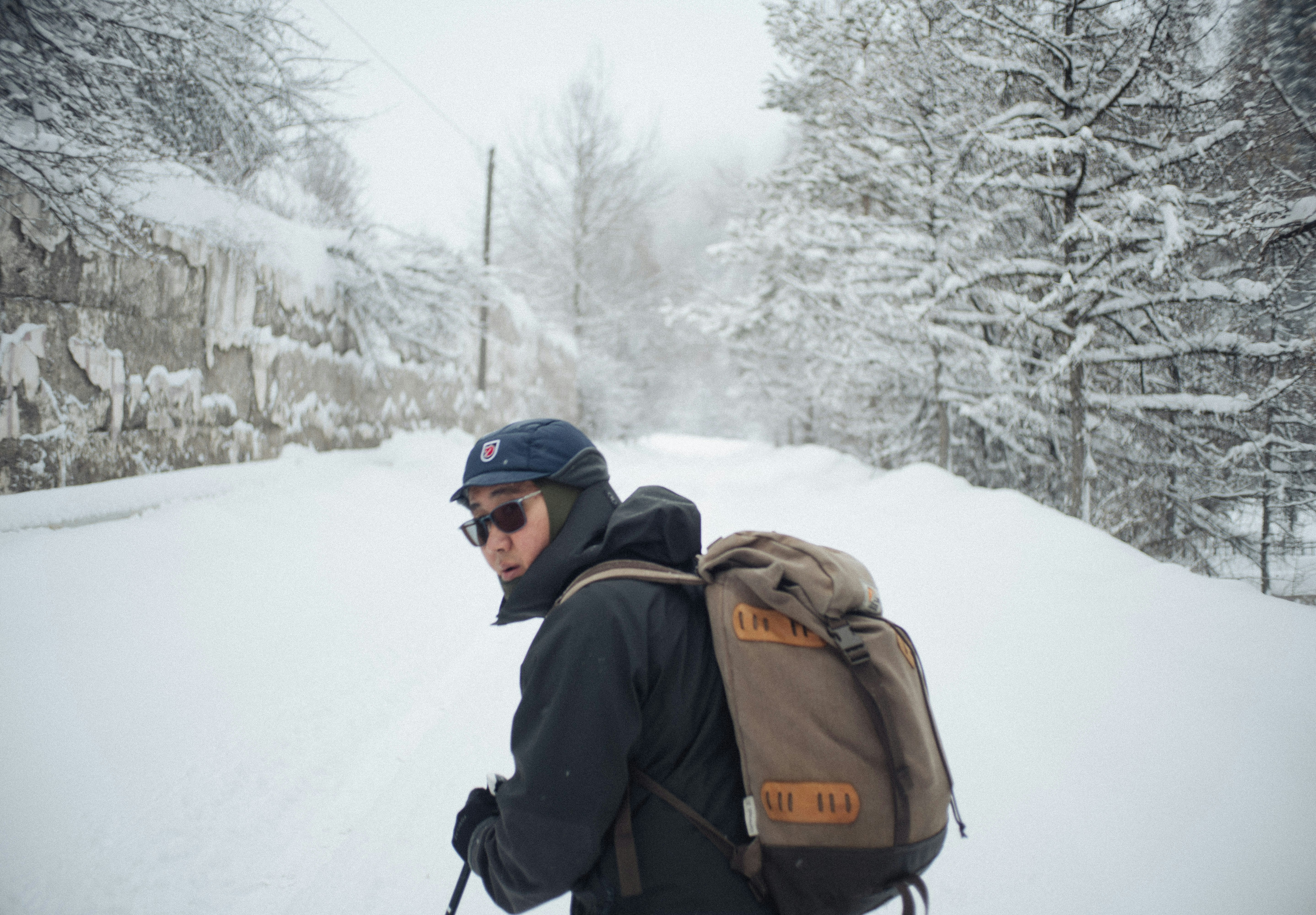 Man with backpack walks on snowy road