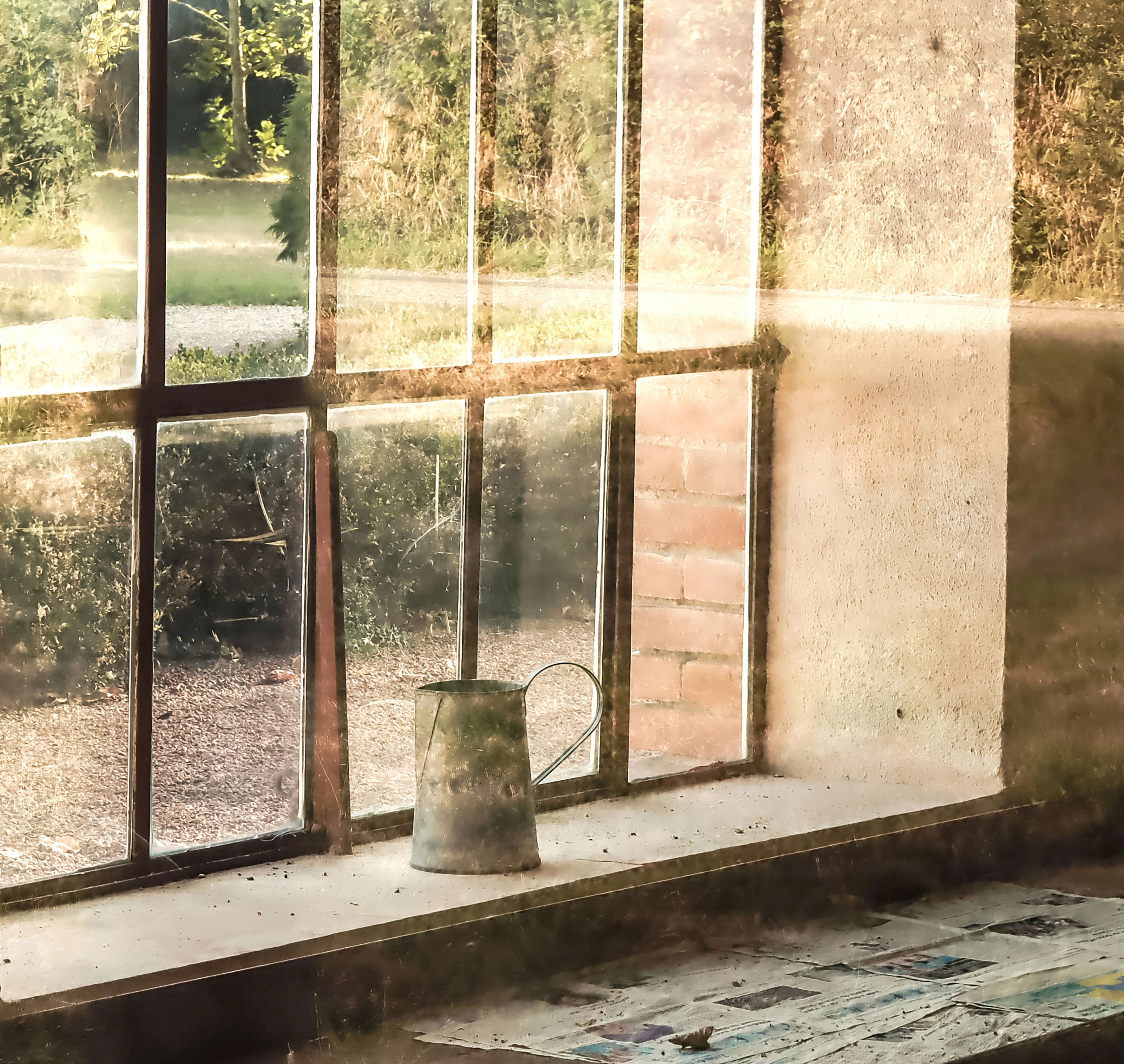 Old watering can on a windowsill with reflections