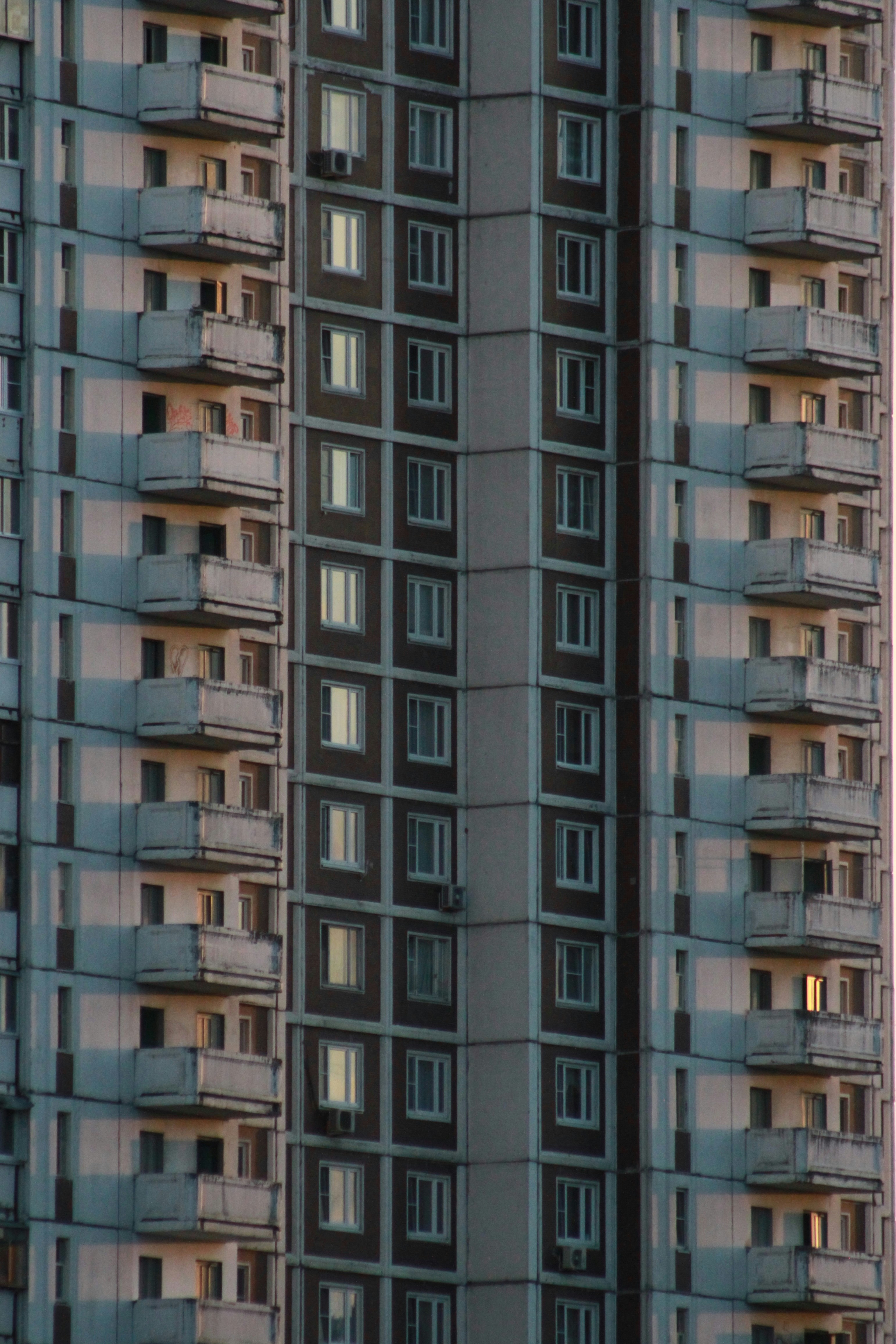 Tall apartment building with many balconies and windows.