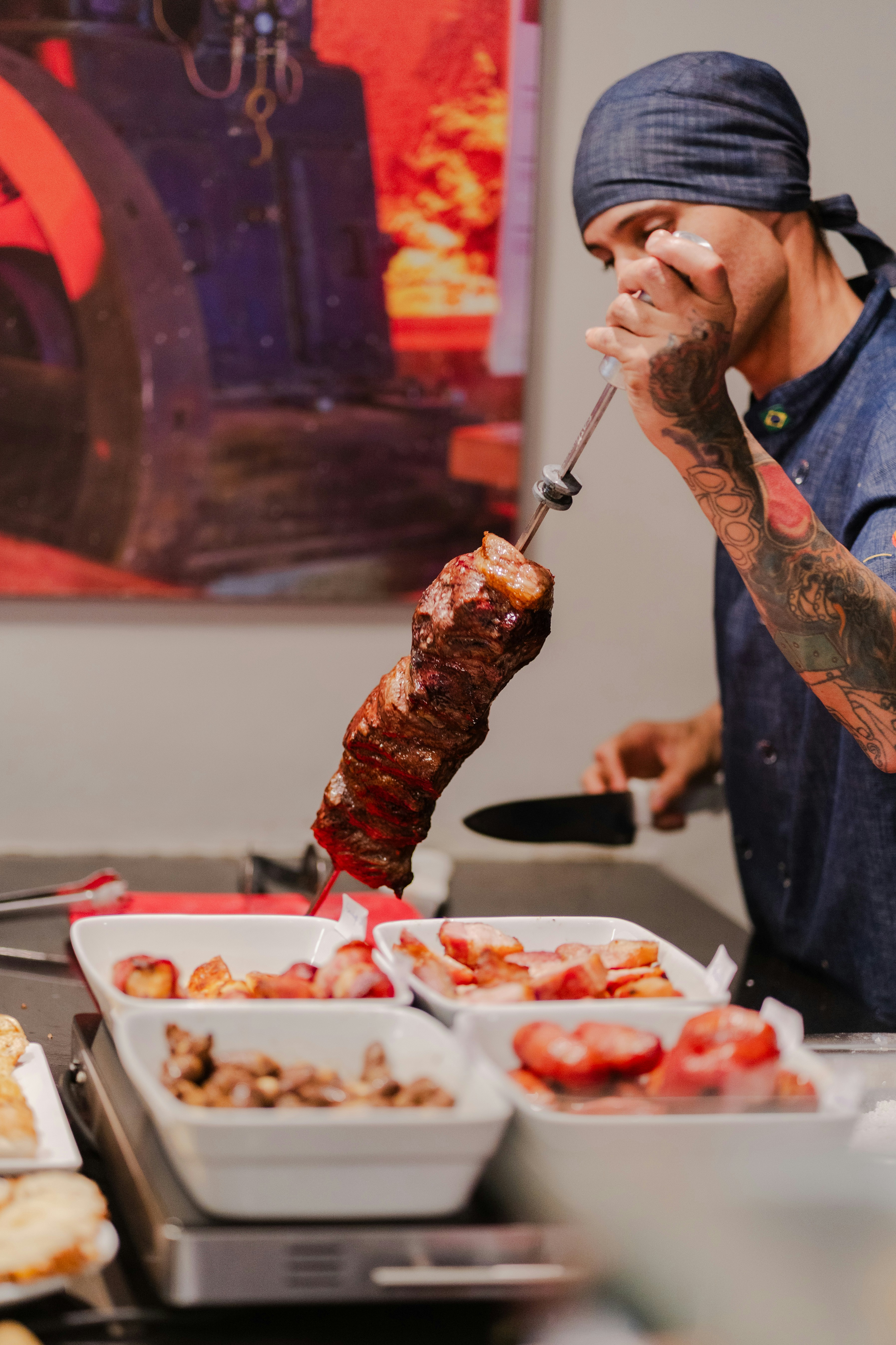 Chef carving a large piece of meat from skewer.