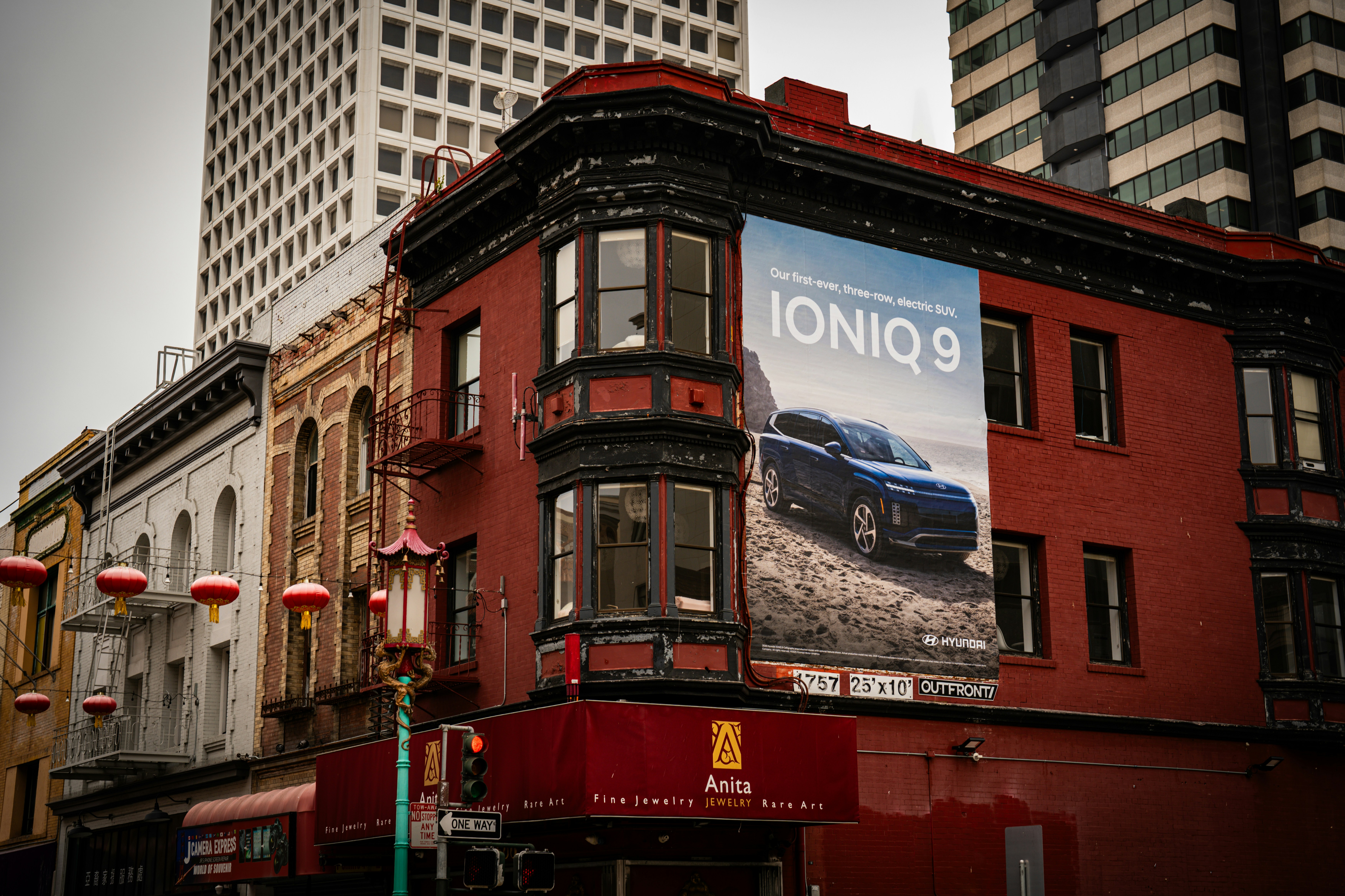Prominent advertisement for the IONIQ 9 displayed on a historic building in an urban setting, surrounded by traditional lanterns.