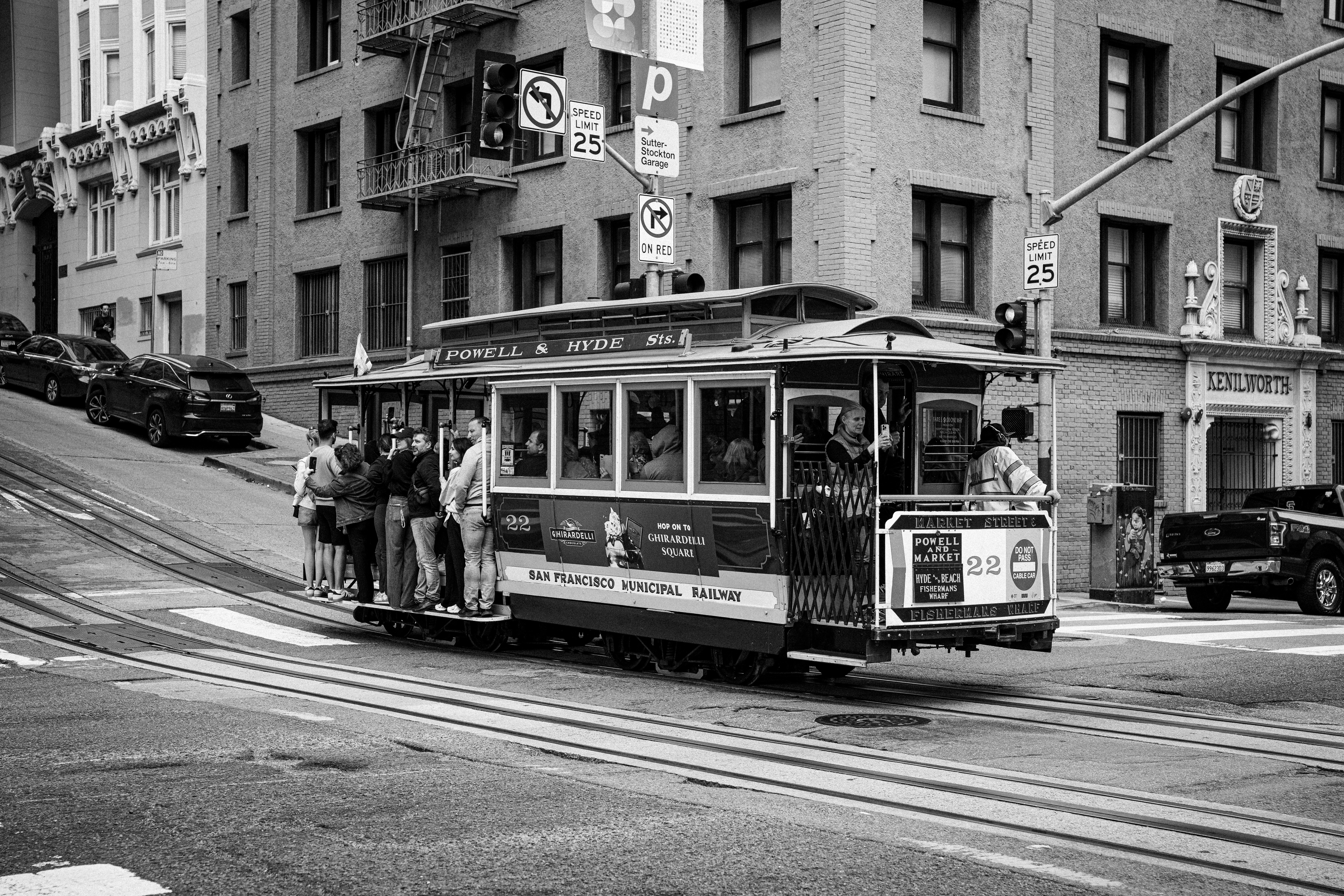 Historic cable car navigates a steep San Francisco street, filled with passengers enjoying the ride. The scene captures the essence of city life.