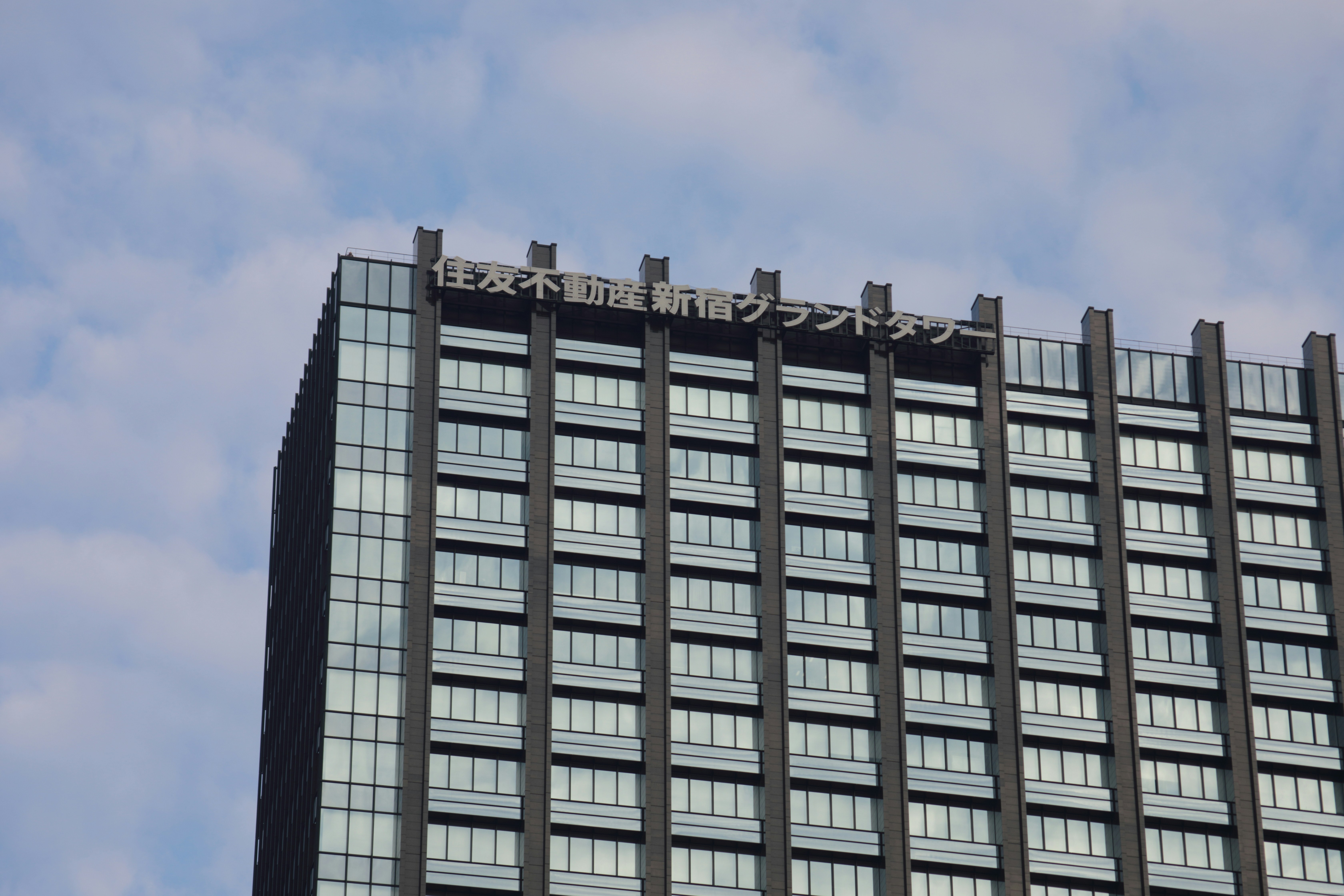 A sleek high-rise building with a reflective glass facade, showcasing modern architectural design against a cloudy sky.