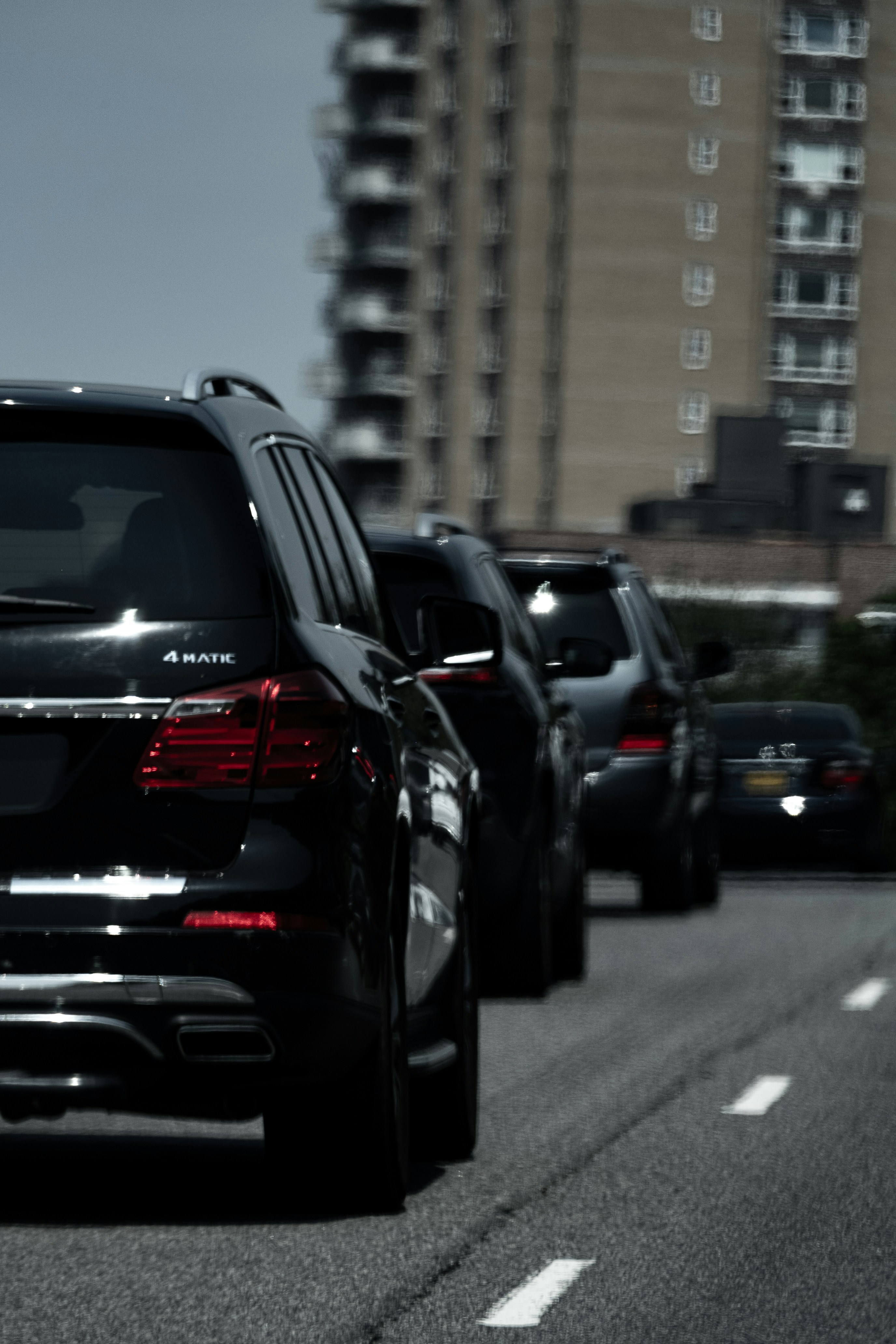 Several black cars driving on a city street. photo – Free Car Image on ...