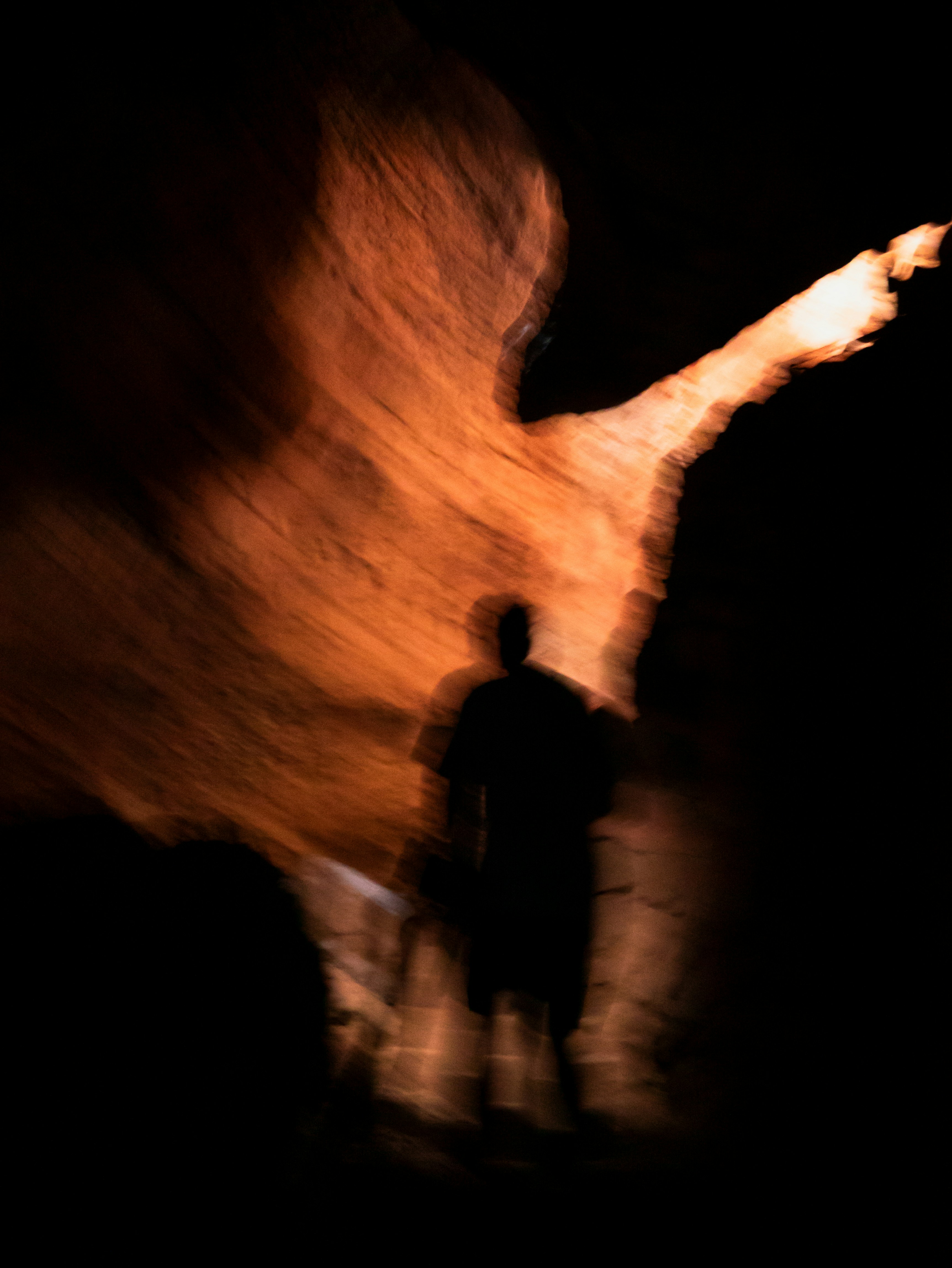Silhouette in a Torch-Lit Cavern: Blurred Motion Against Glowing Stone