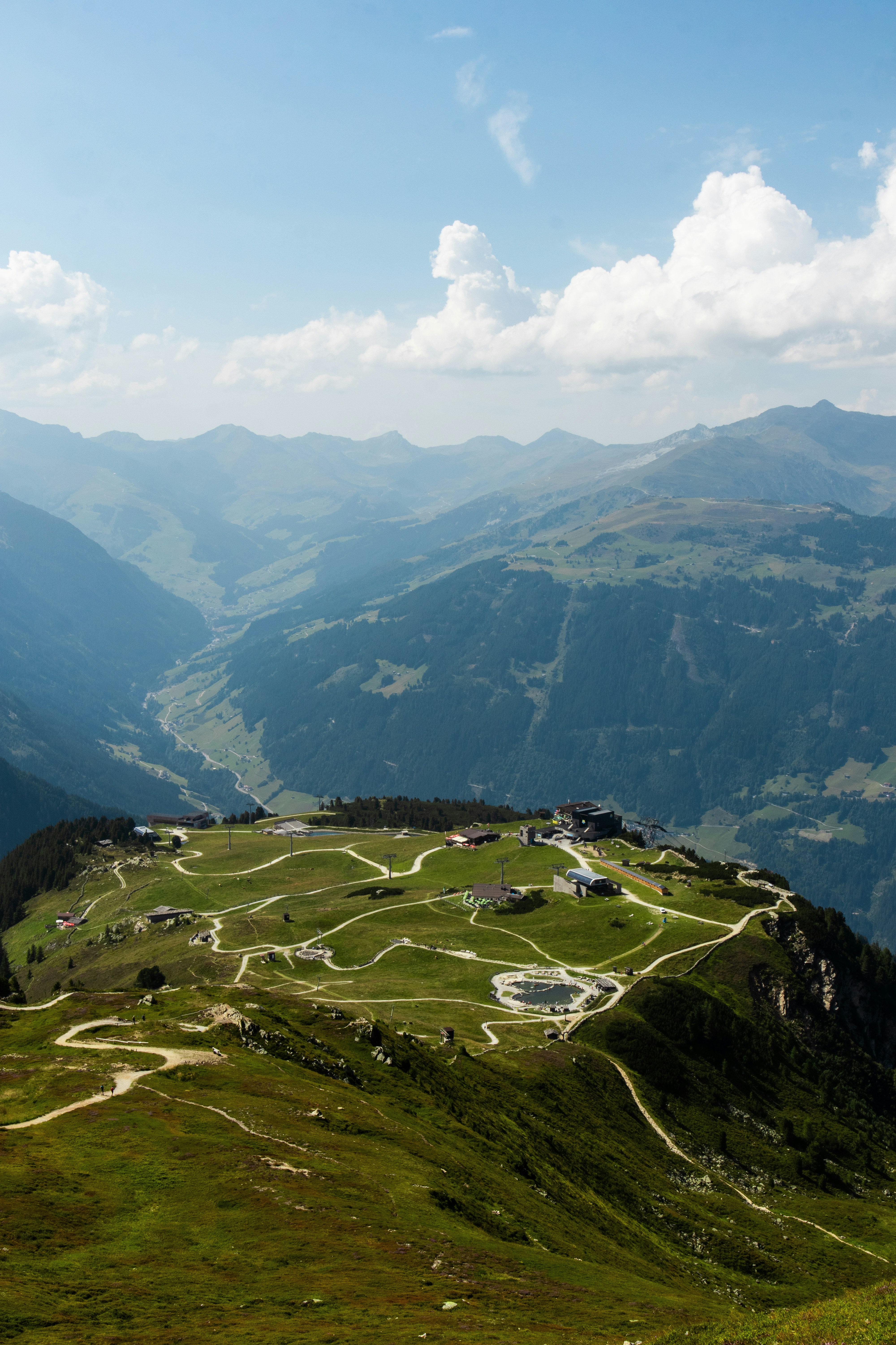 Green mountain plateau with winding paths and distant valley.