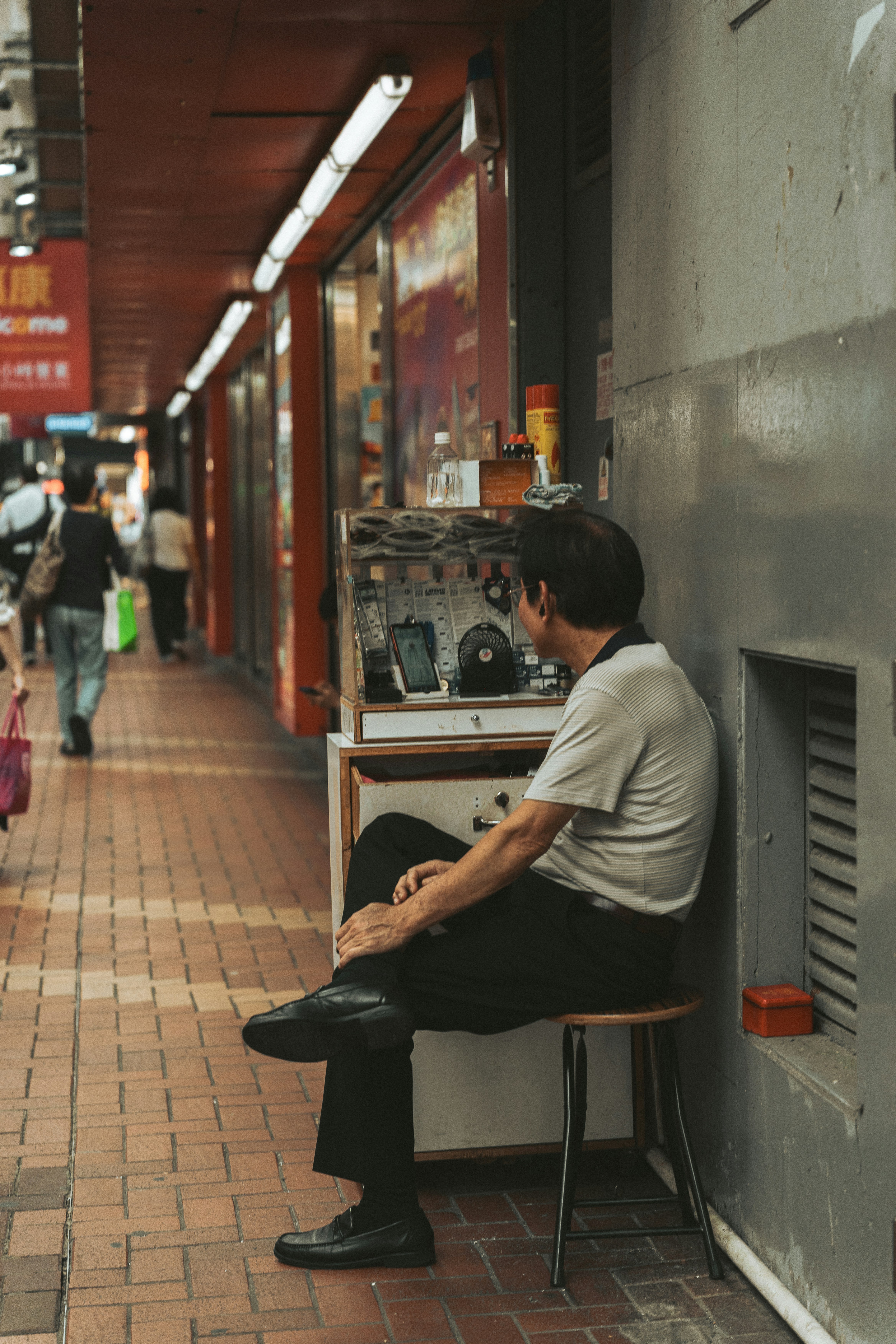 Man sitting outside a shop on a city street.
