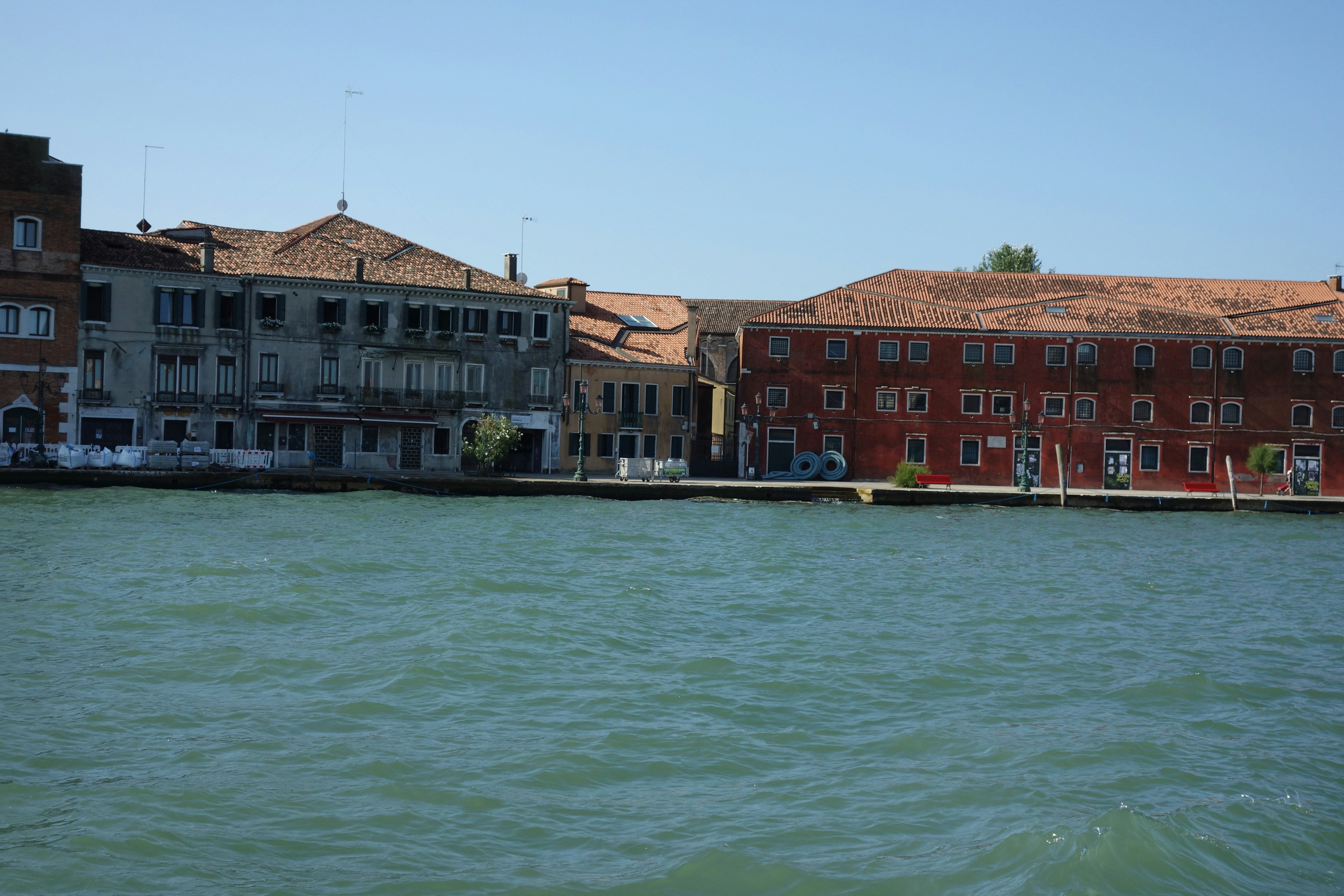 Historic buildings line the waterfront in Venice, showcasing a blend of architectural styles and vibrant colors against the serene water backdrop.