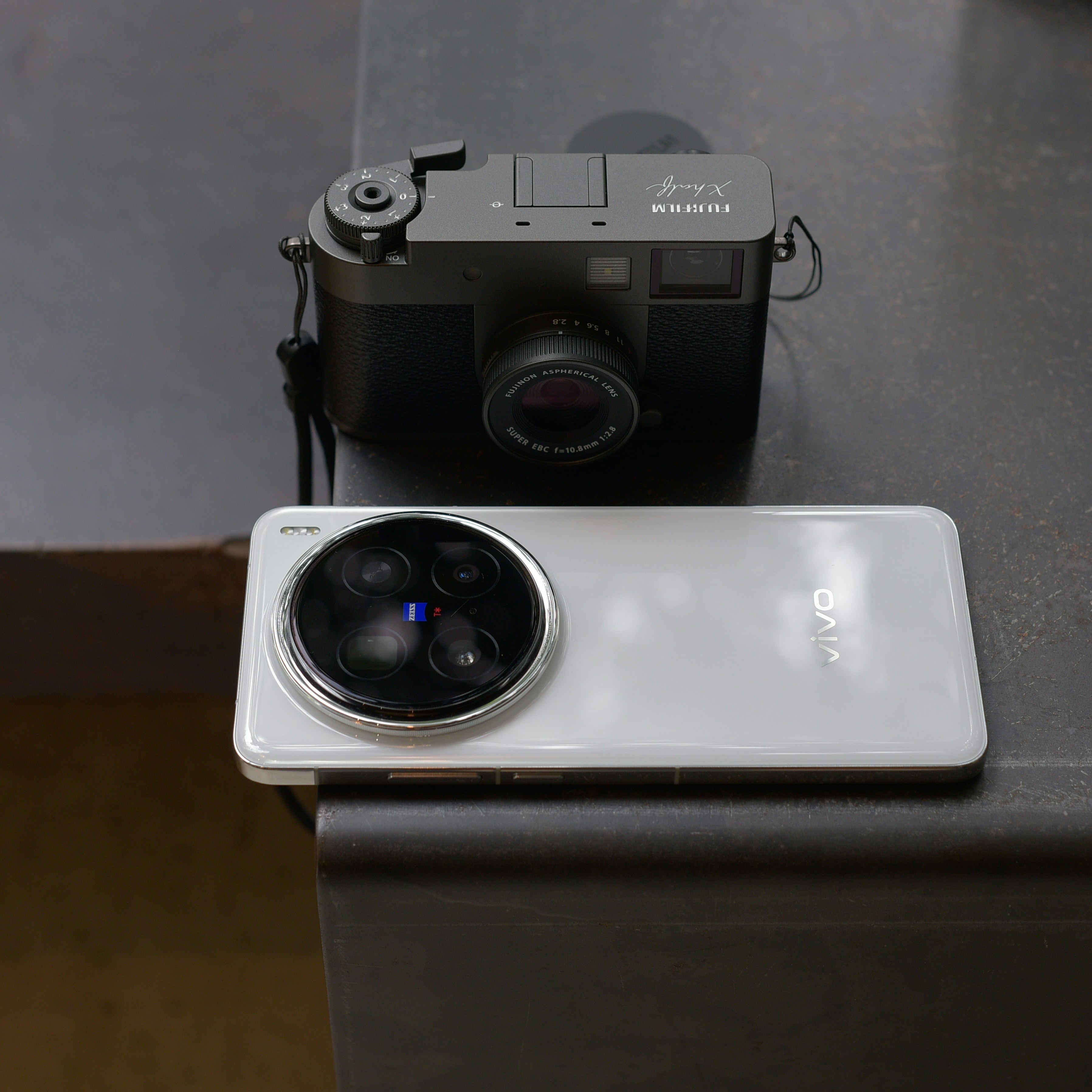 Vivo X200 Pro, Fujifilm Xhalf | Camera and smartphone with large lens on table