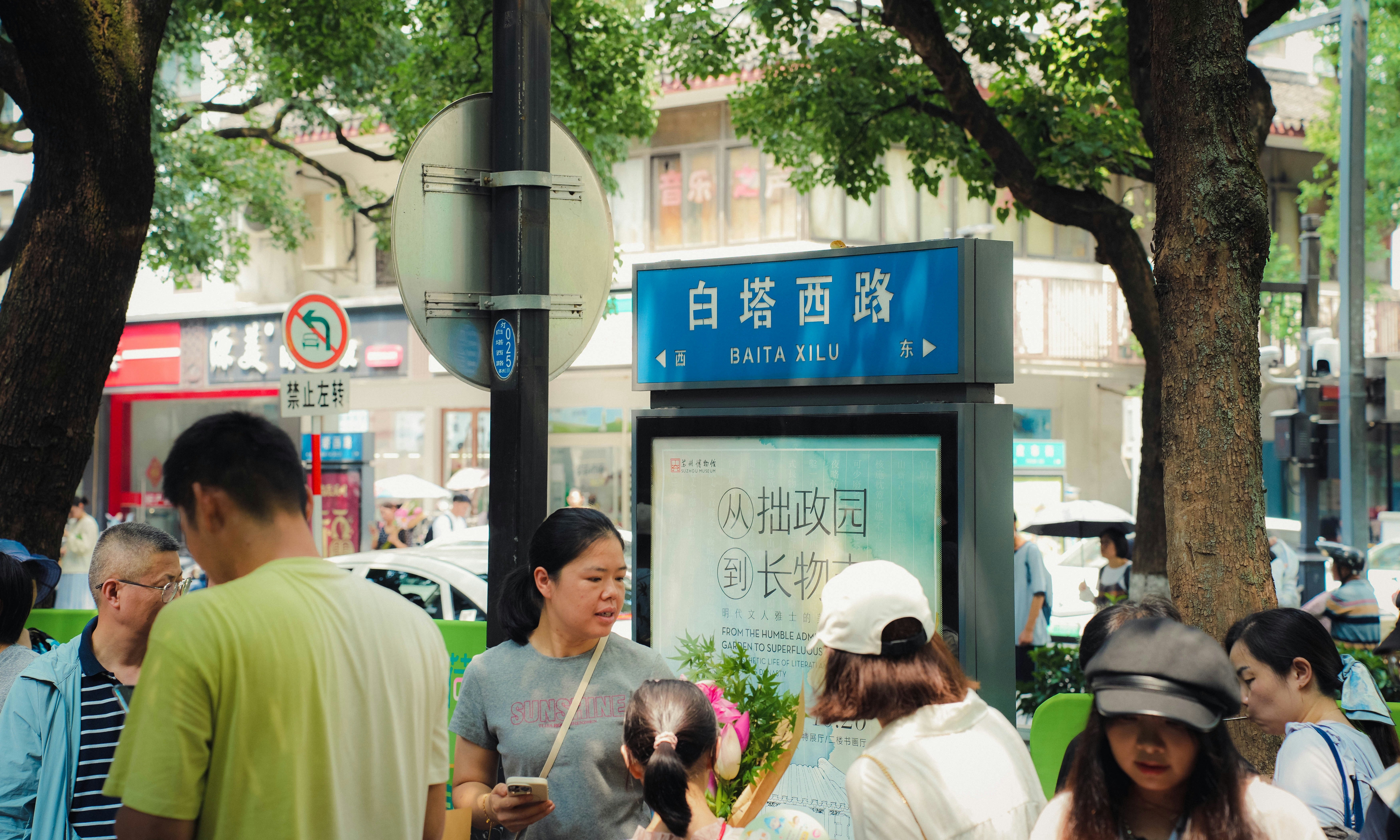 People gathered near a street sign in a city.