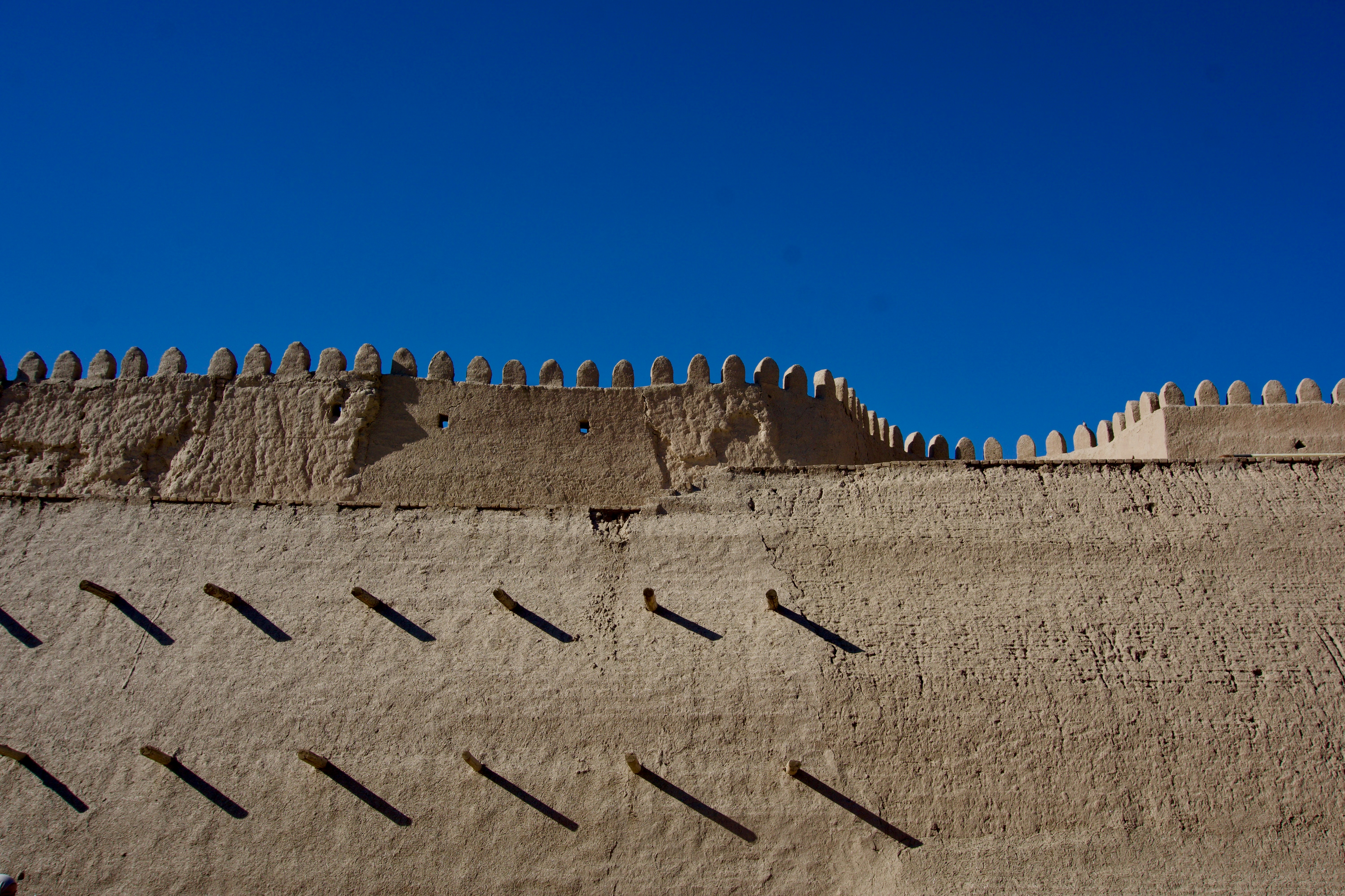 Ancient stone wall with crenellations against blue sky
