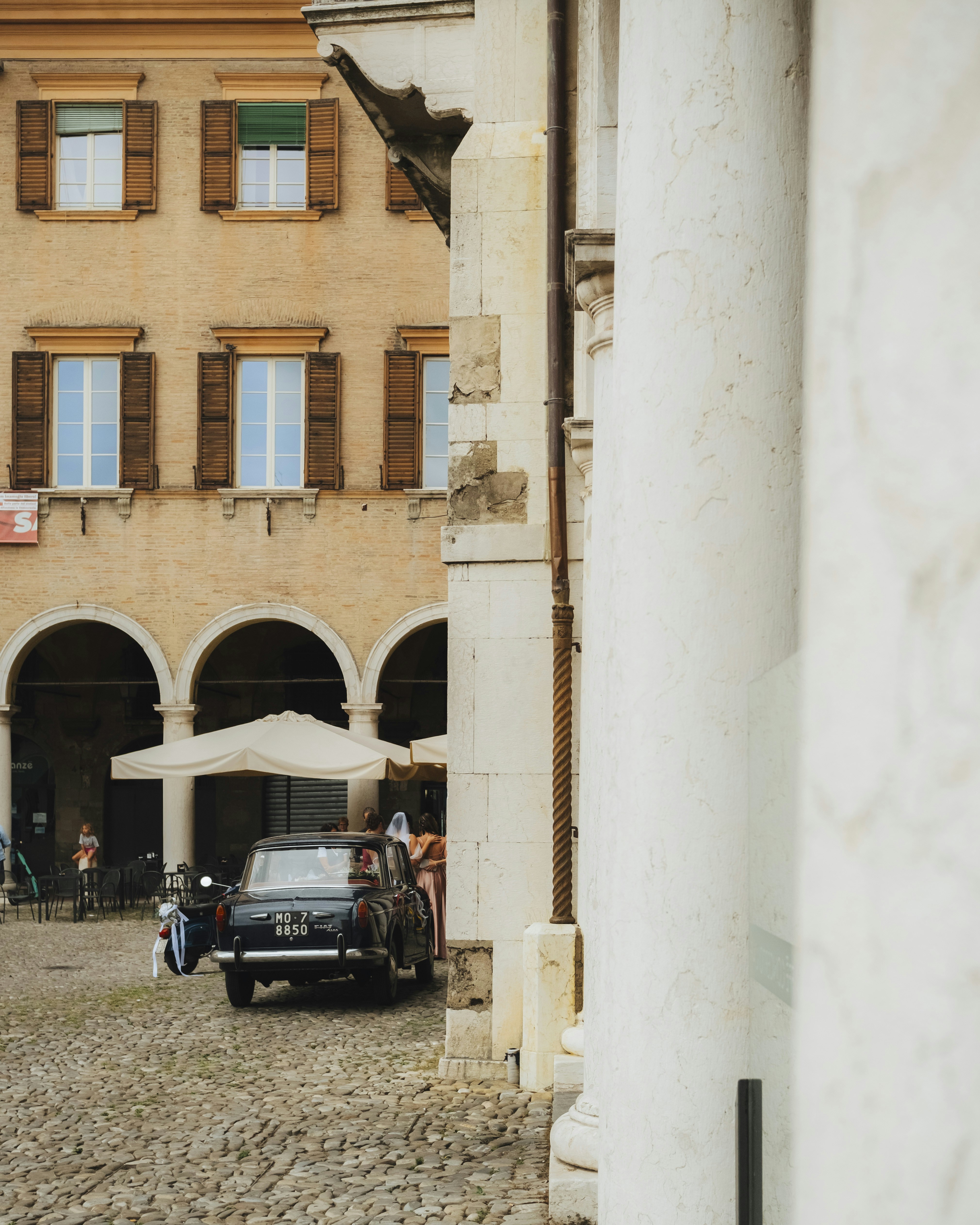 Vintage car parked on cobblestone street near building.