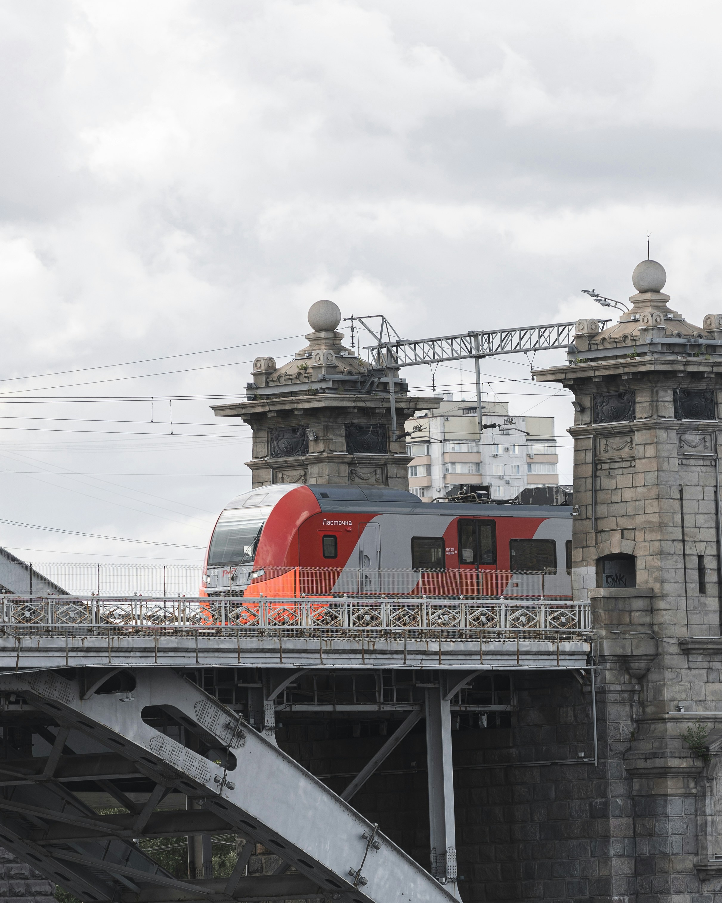 Modern train crossing a historic stone bridge under a cloudy sky, showcasing the blend of contemporary and classic design elements.