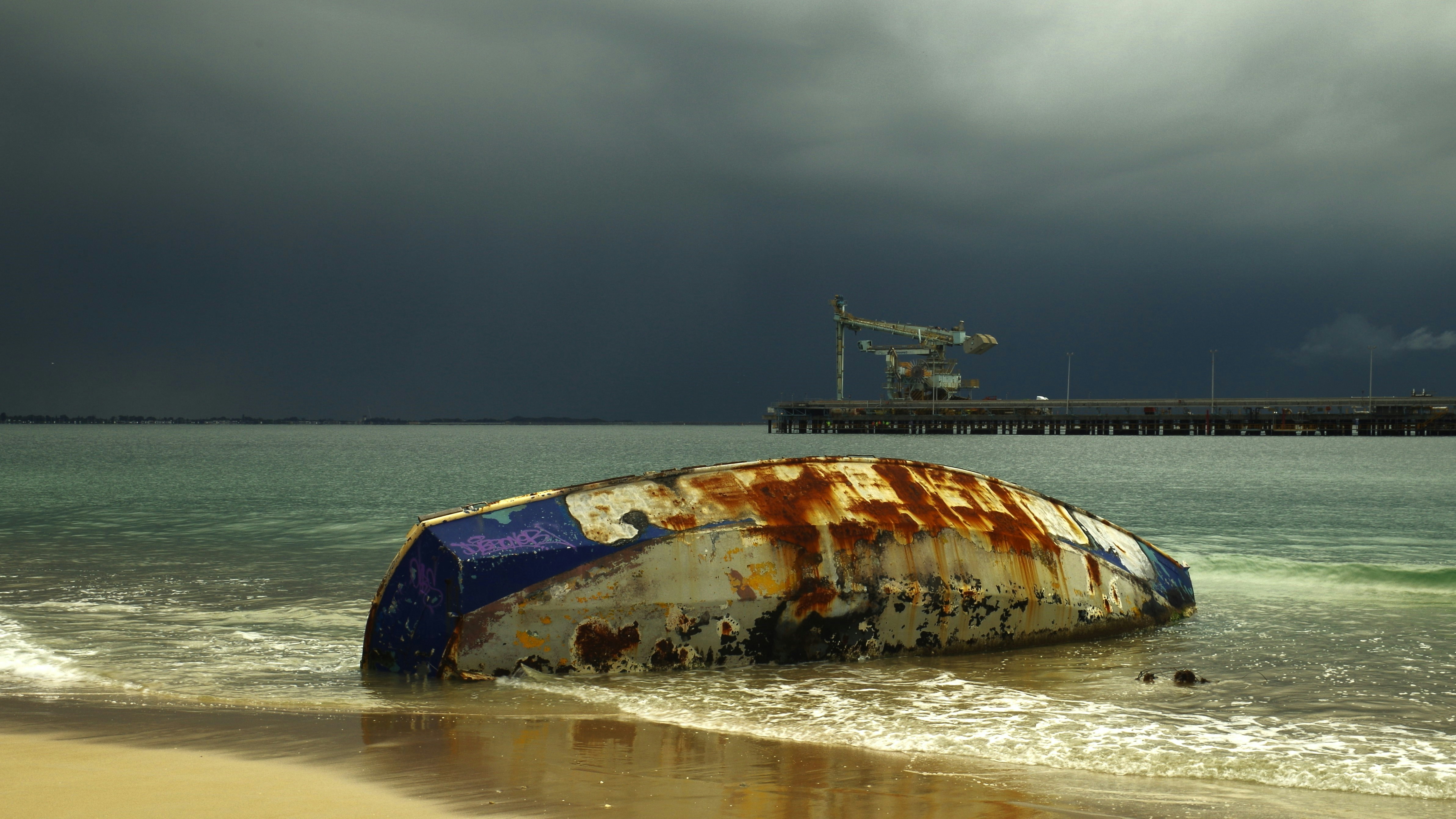 A wrecked boat on the shore of Kwinana beach Western Australia | Wrecked boat washed ashore on a sandy beach.