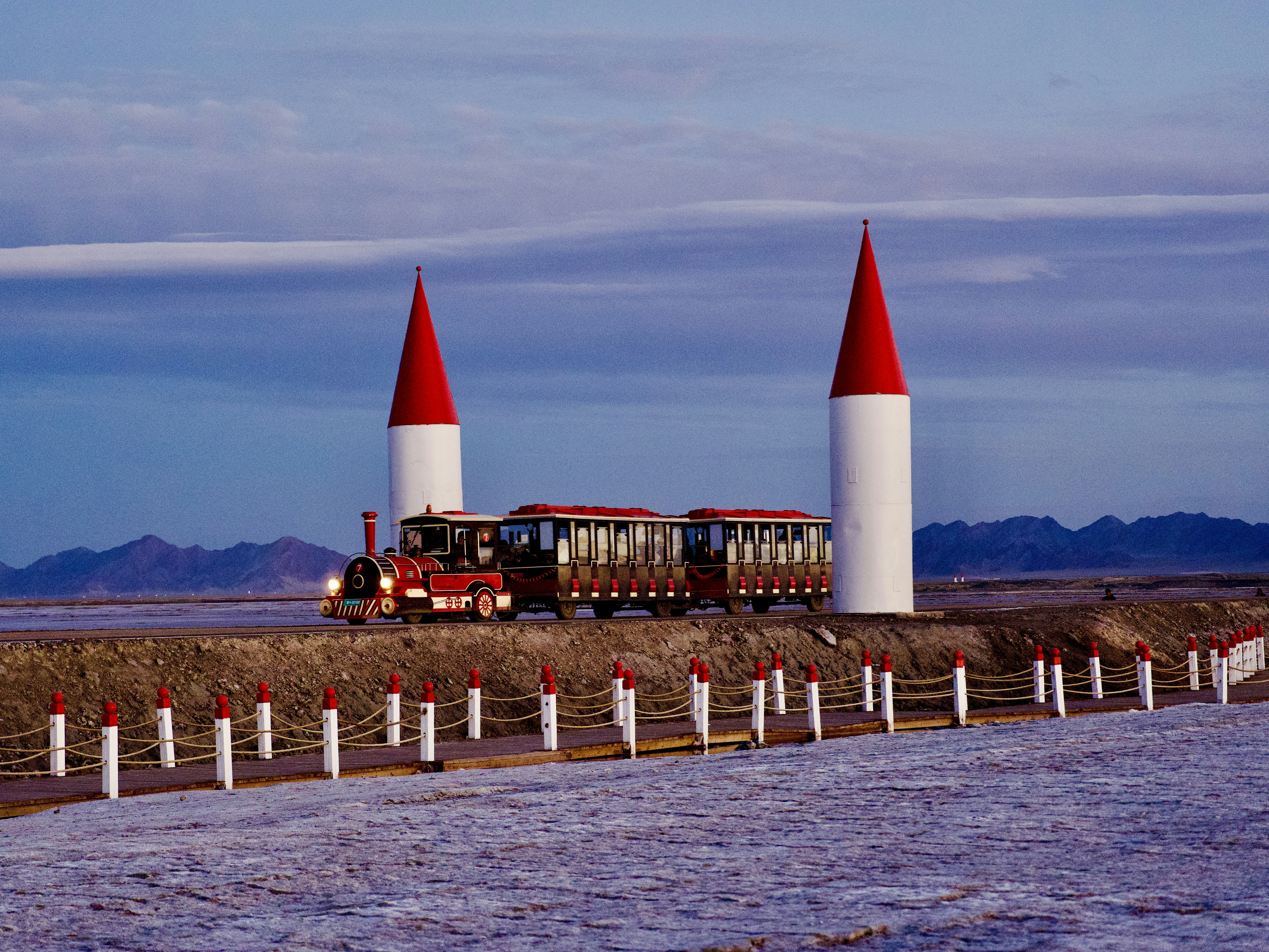 Tourist train passes between two white towers.