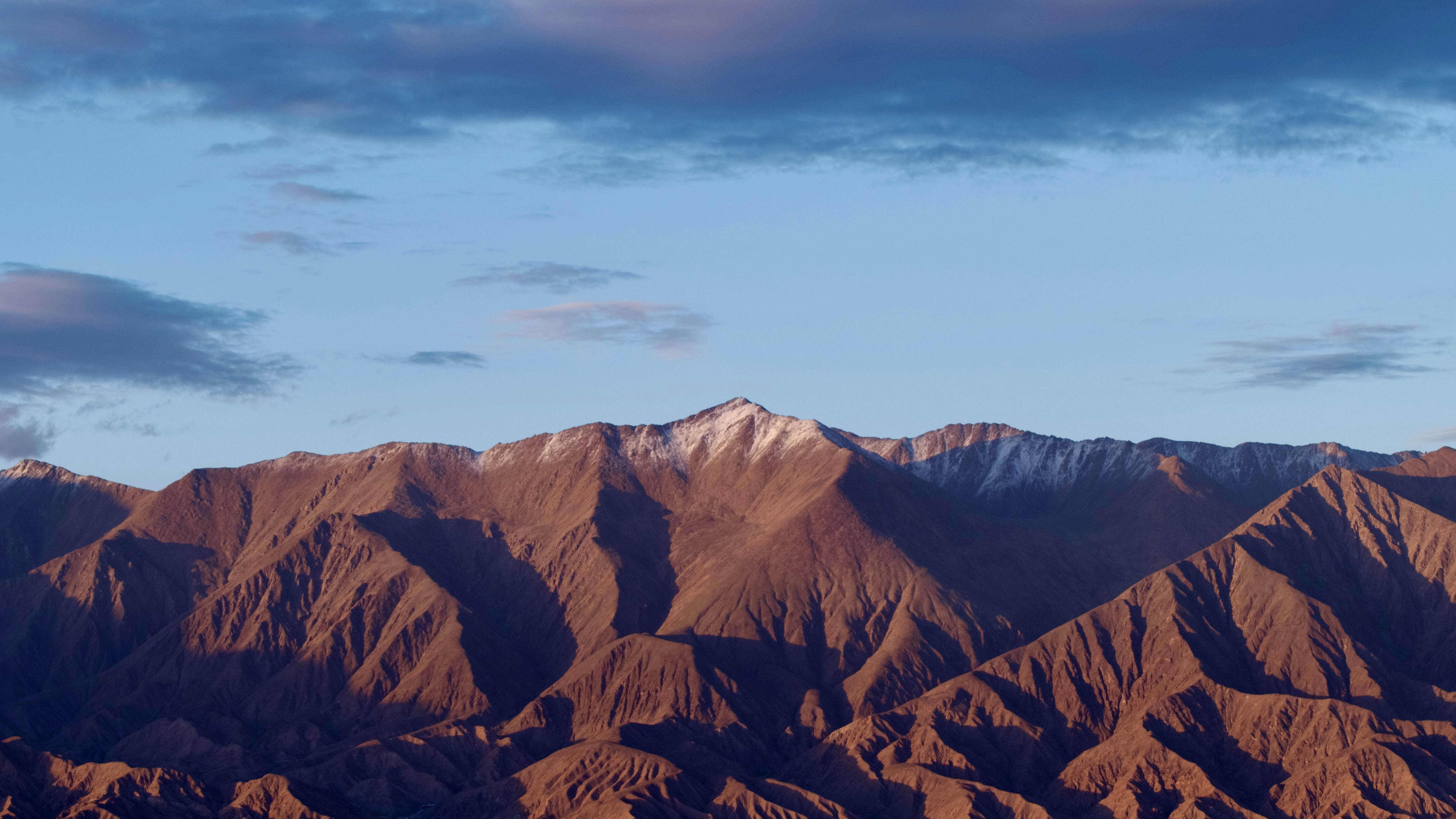 When the last glow of dusk crosses the horizon to kiss the sleeping ridges. | Majestic mountain range illuminated by golden hour sunlight