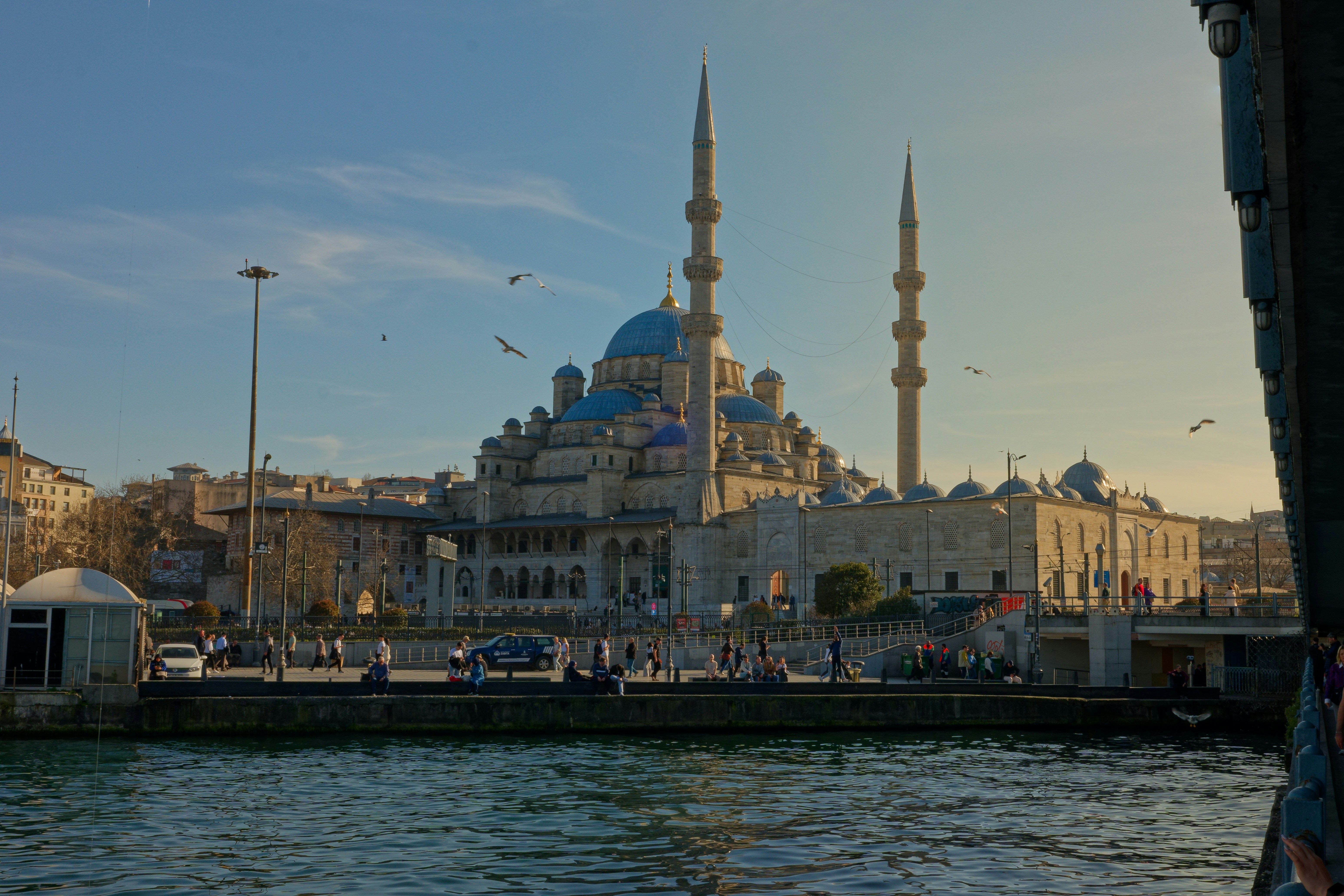 Grand mosque with blue domes and minarets by water.