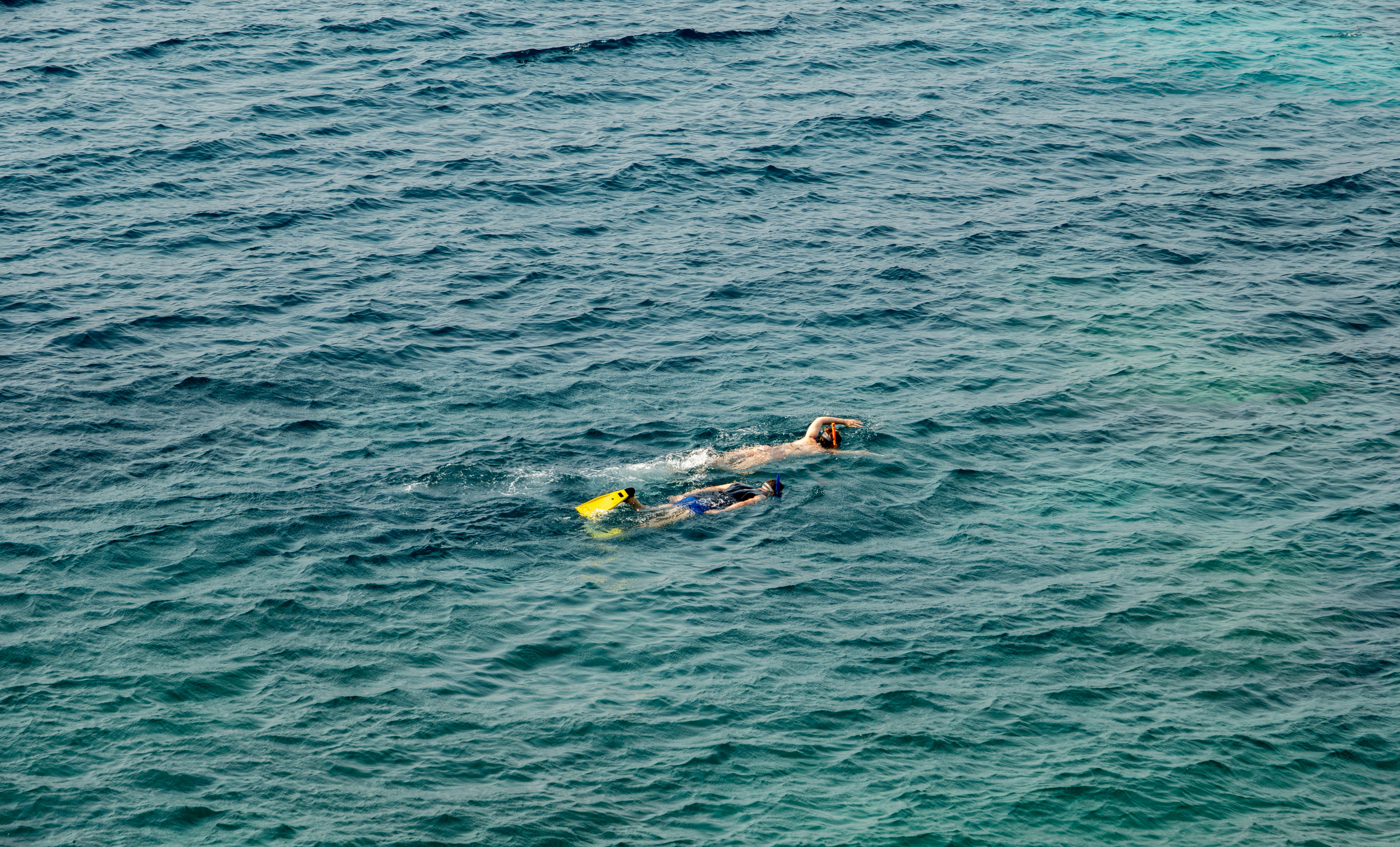 Two people snorkeling in clear blue ocean water