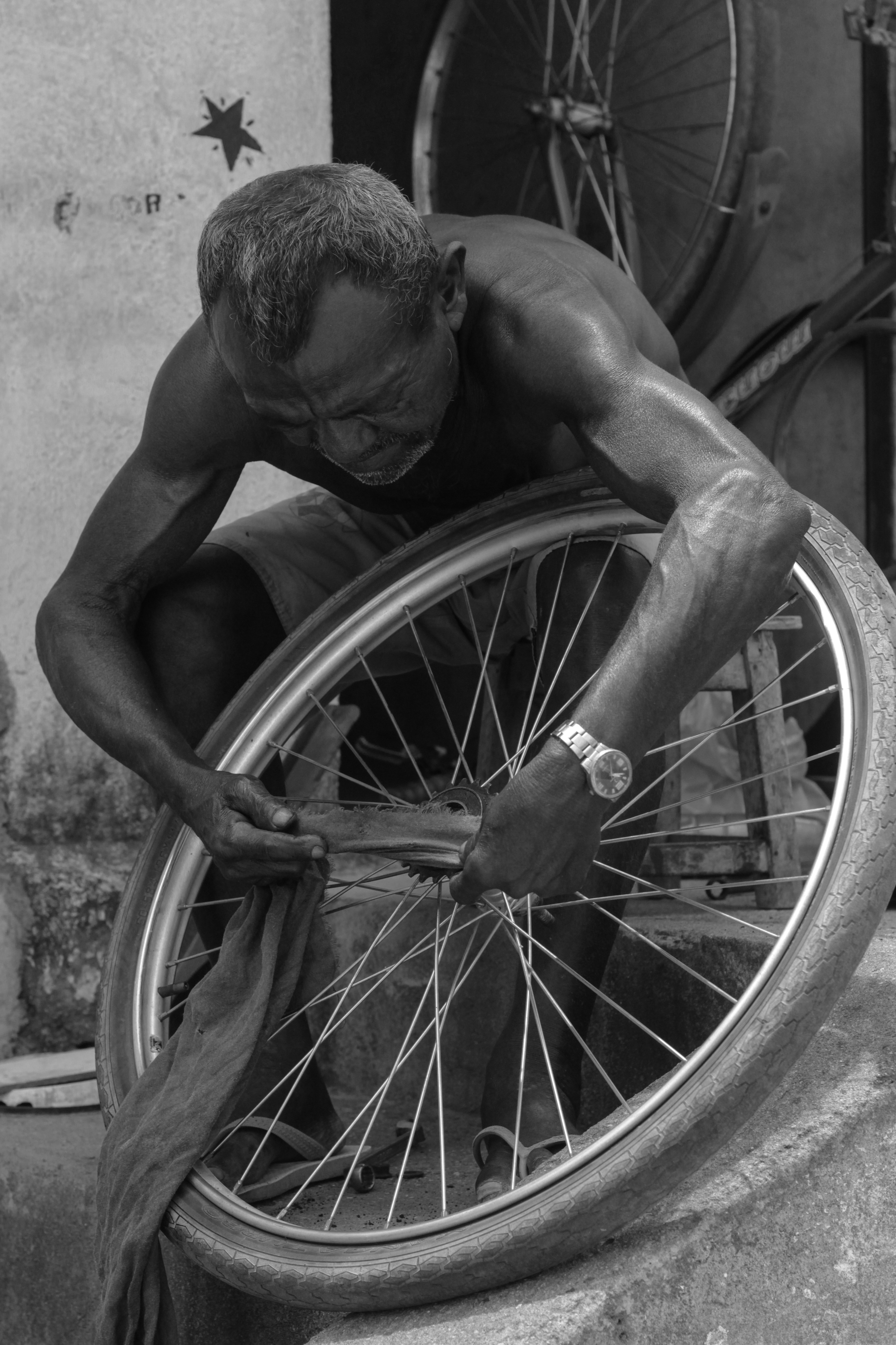 Man repairing a bicycle wheel with a cloth.