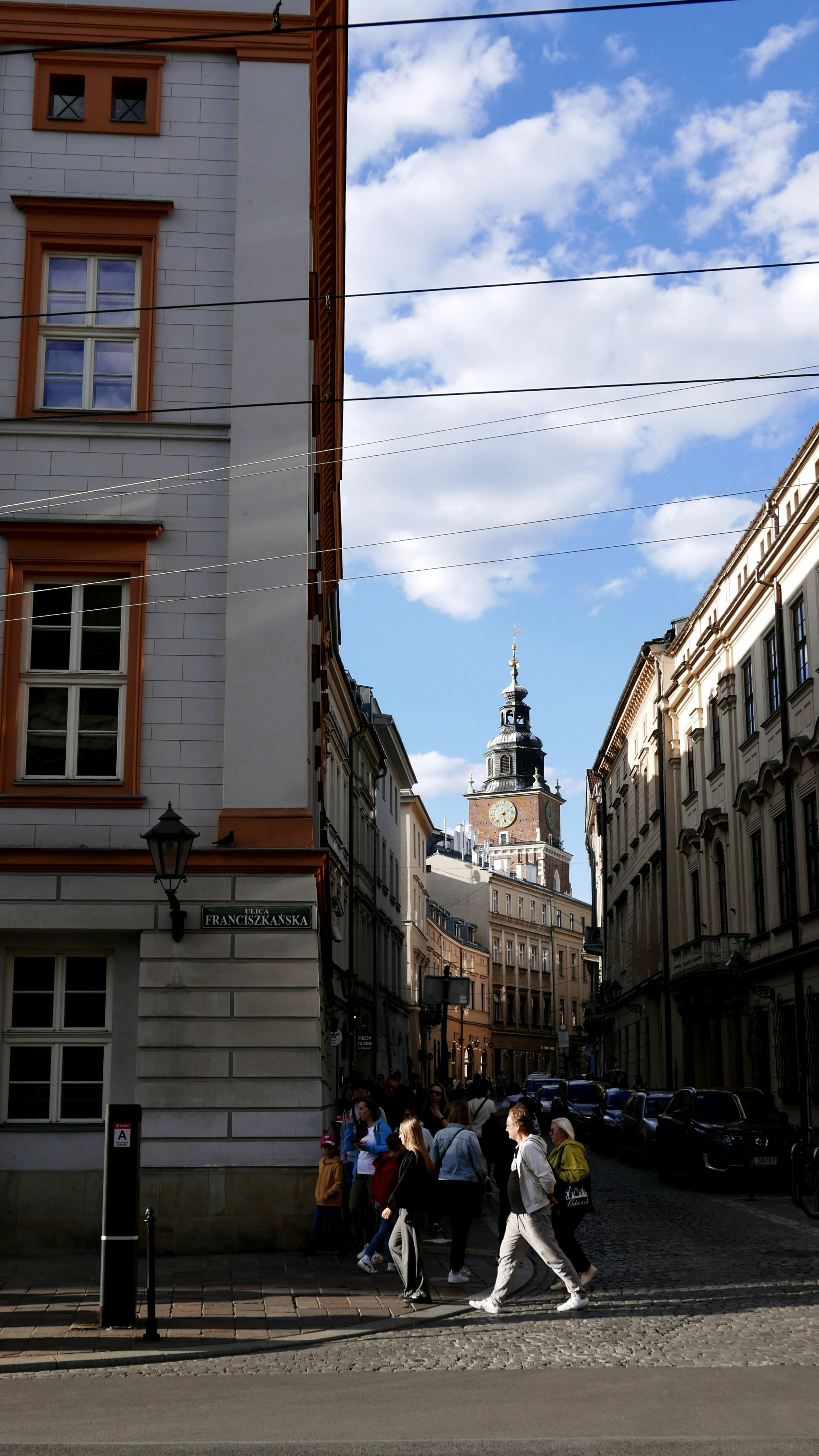 People crossing street towards clock tower in old town