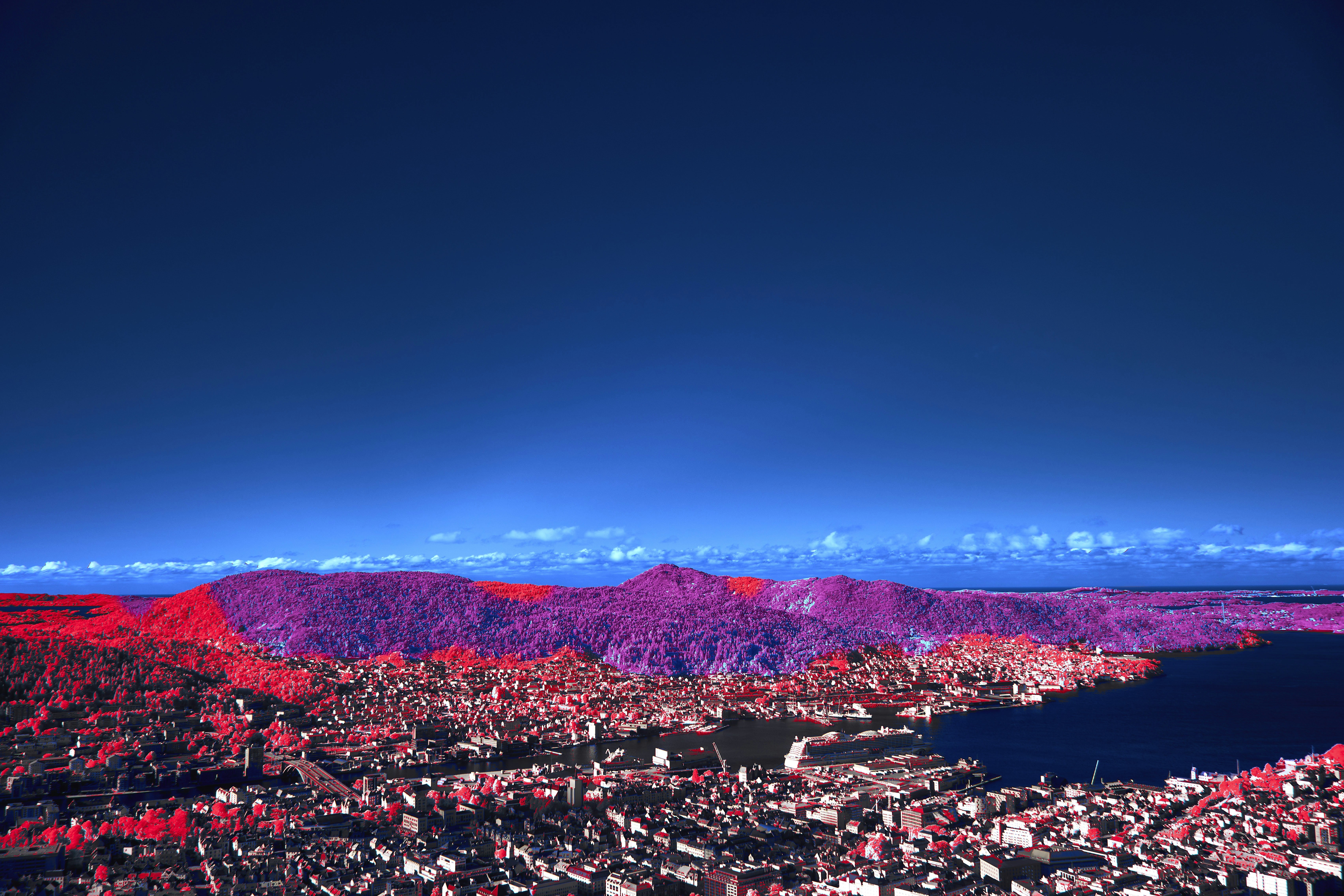 Infrared landscape with mountains and city lights.
