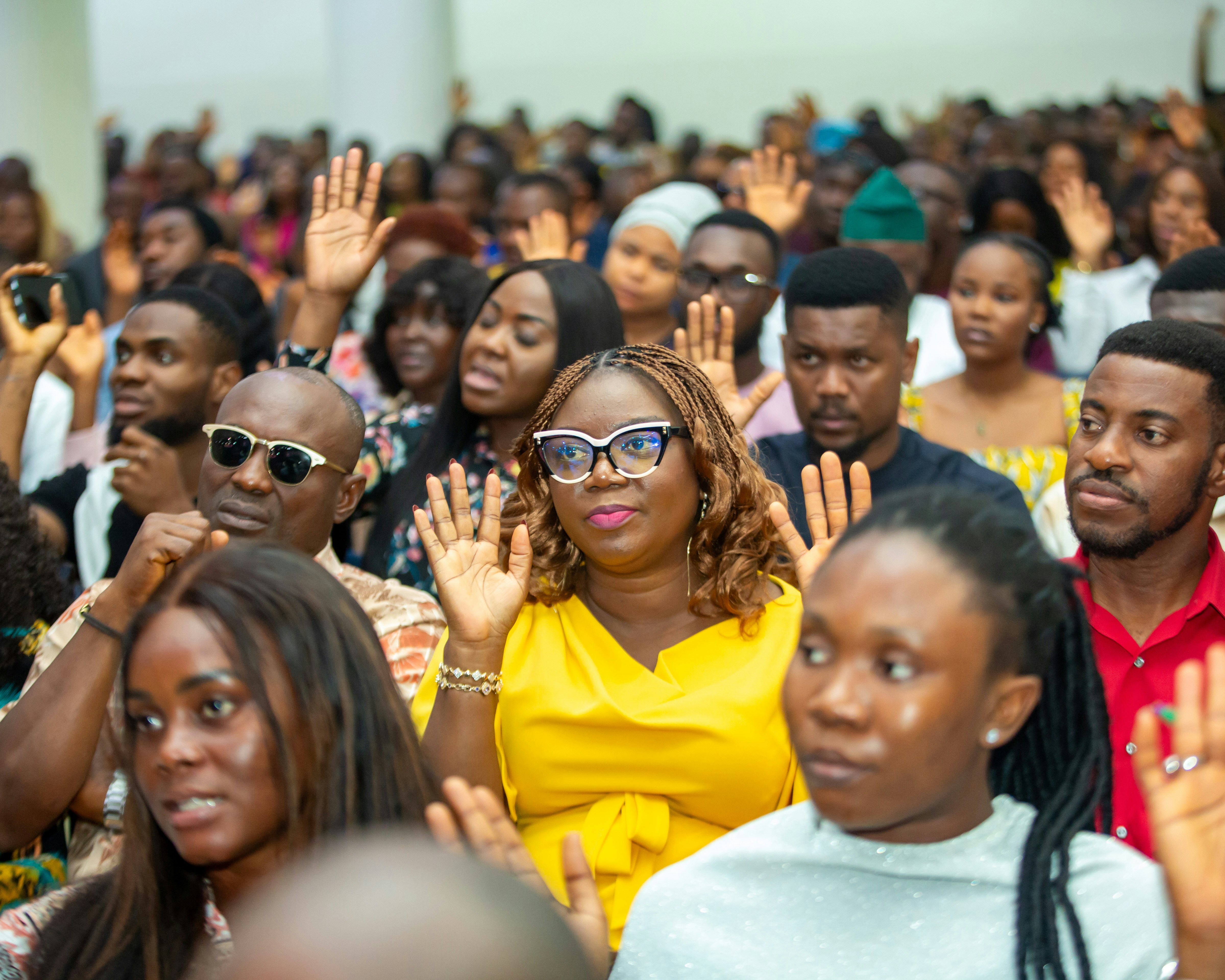 Audience members raising their hands in unison during an event, showcasing engagement and participation.