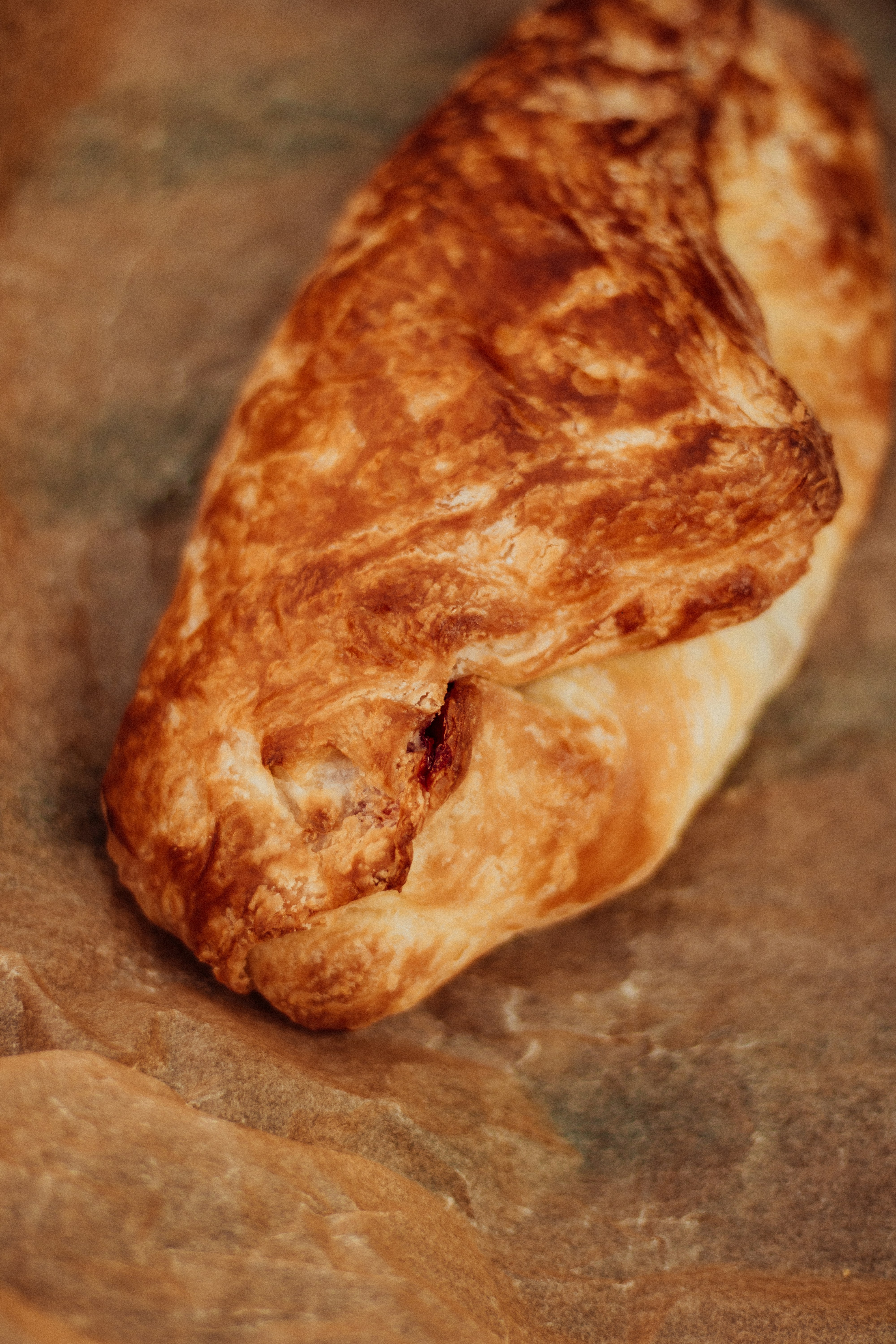 A freshly baked pastry with a golden-brown crust resting on parchment paper.