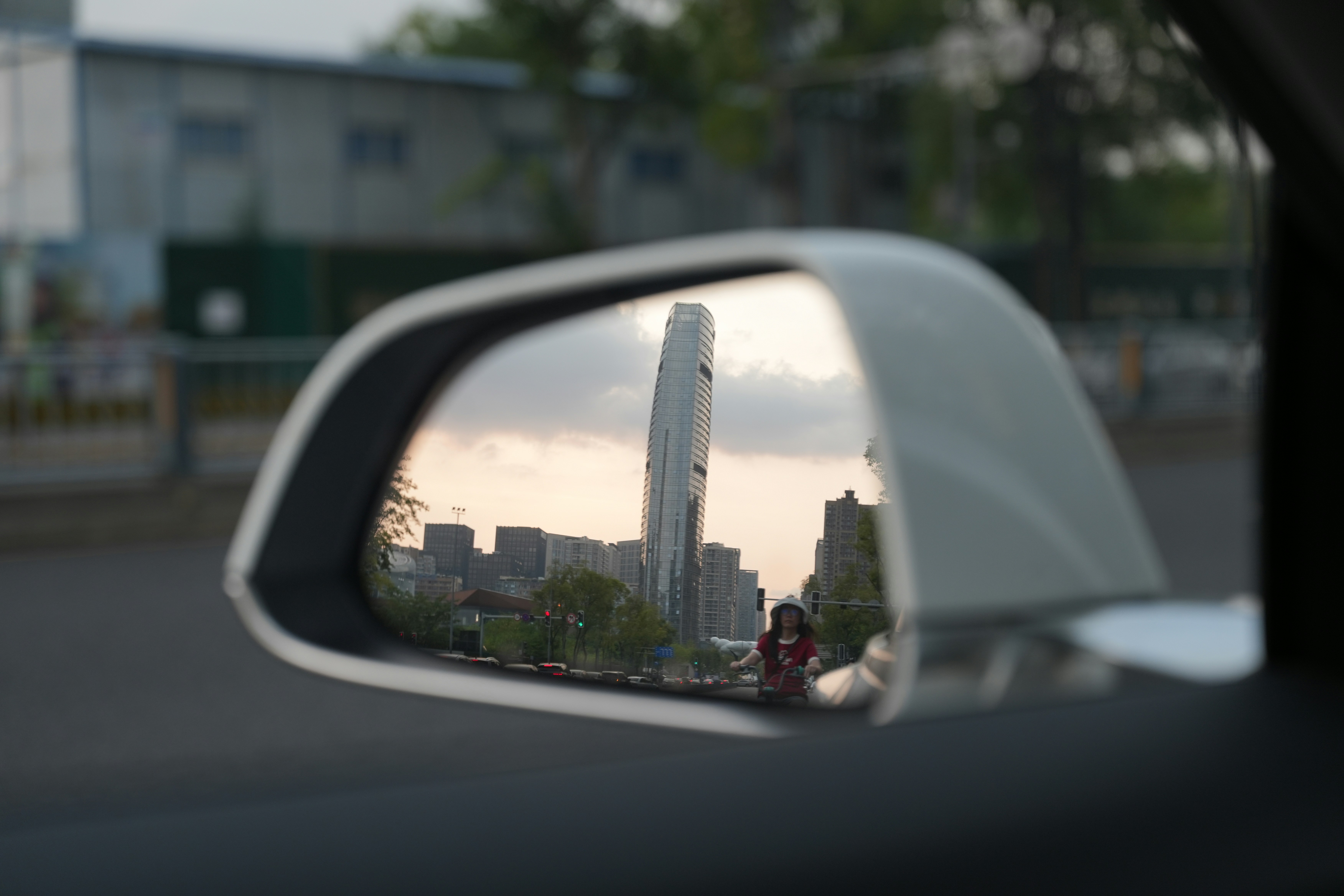 Reflection of a tall building in a car's side mirror.