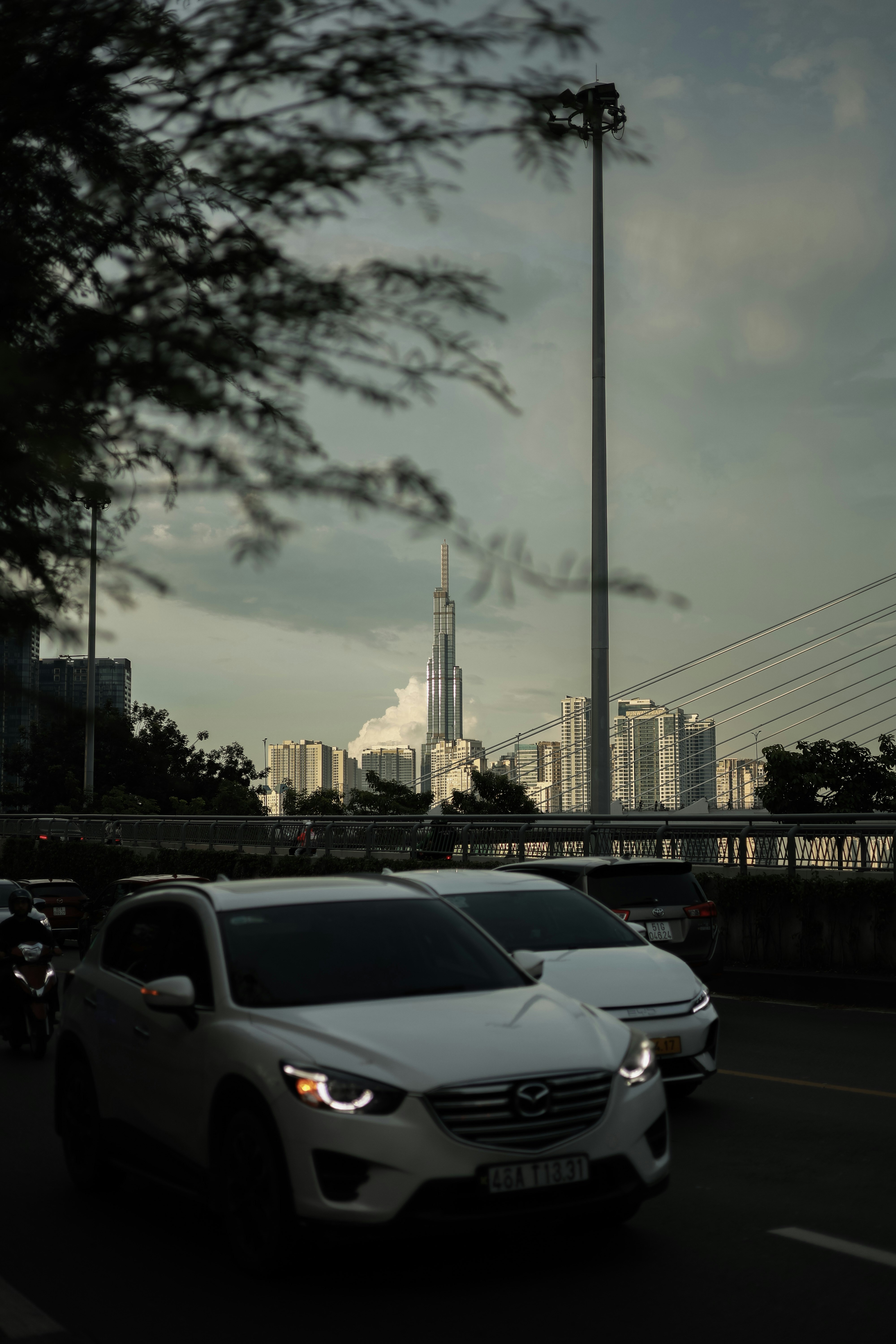 Cars on a road with city skyline and bridge.