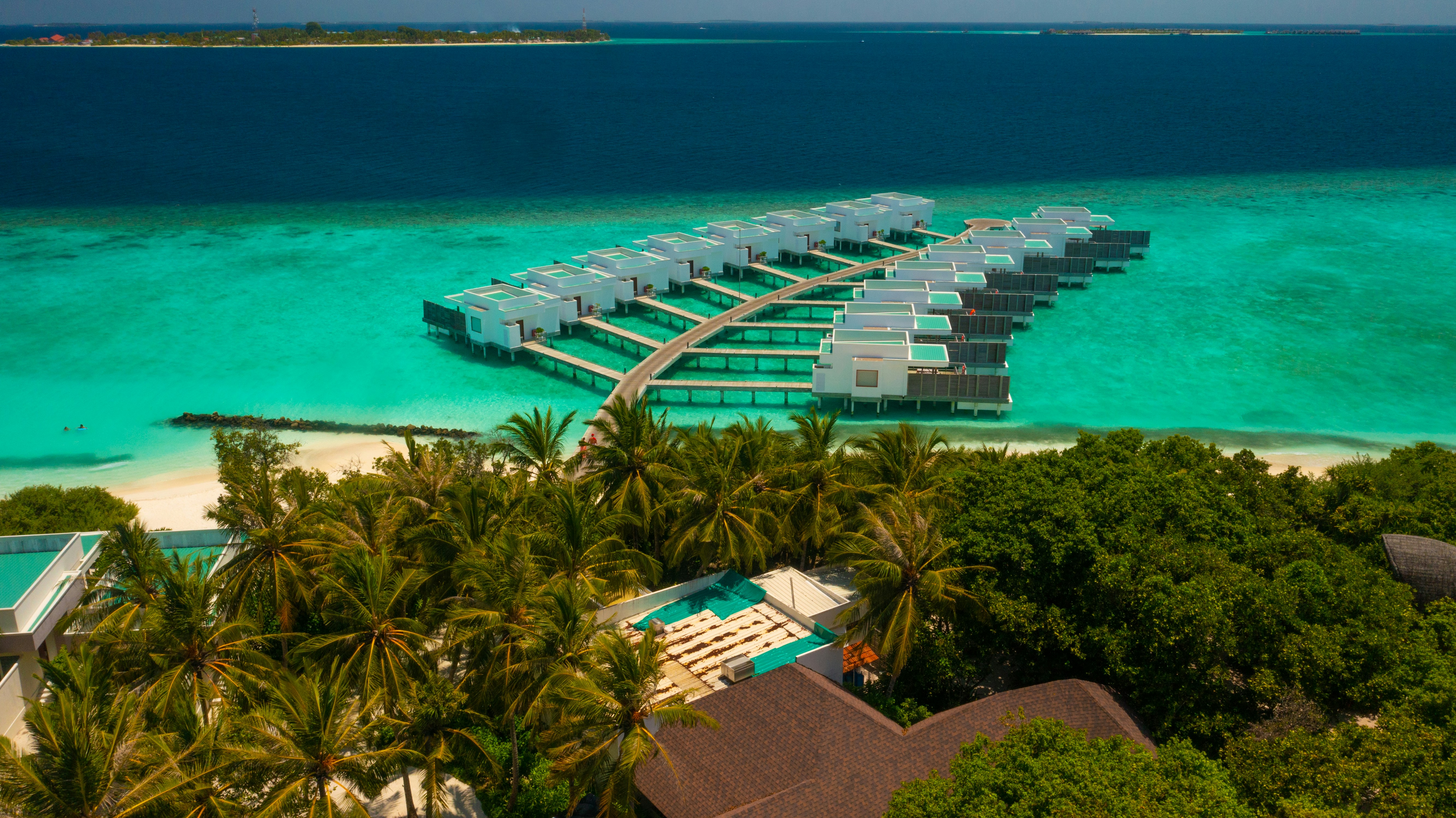 Luxury bungalows over turquoise water with palm trees