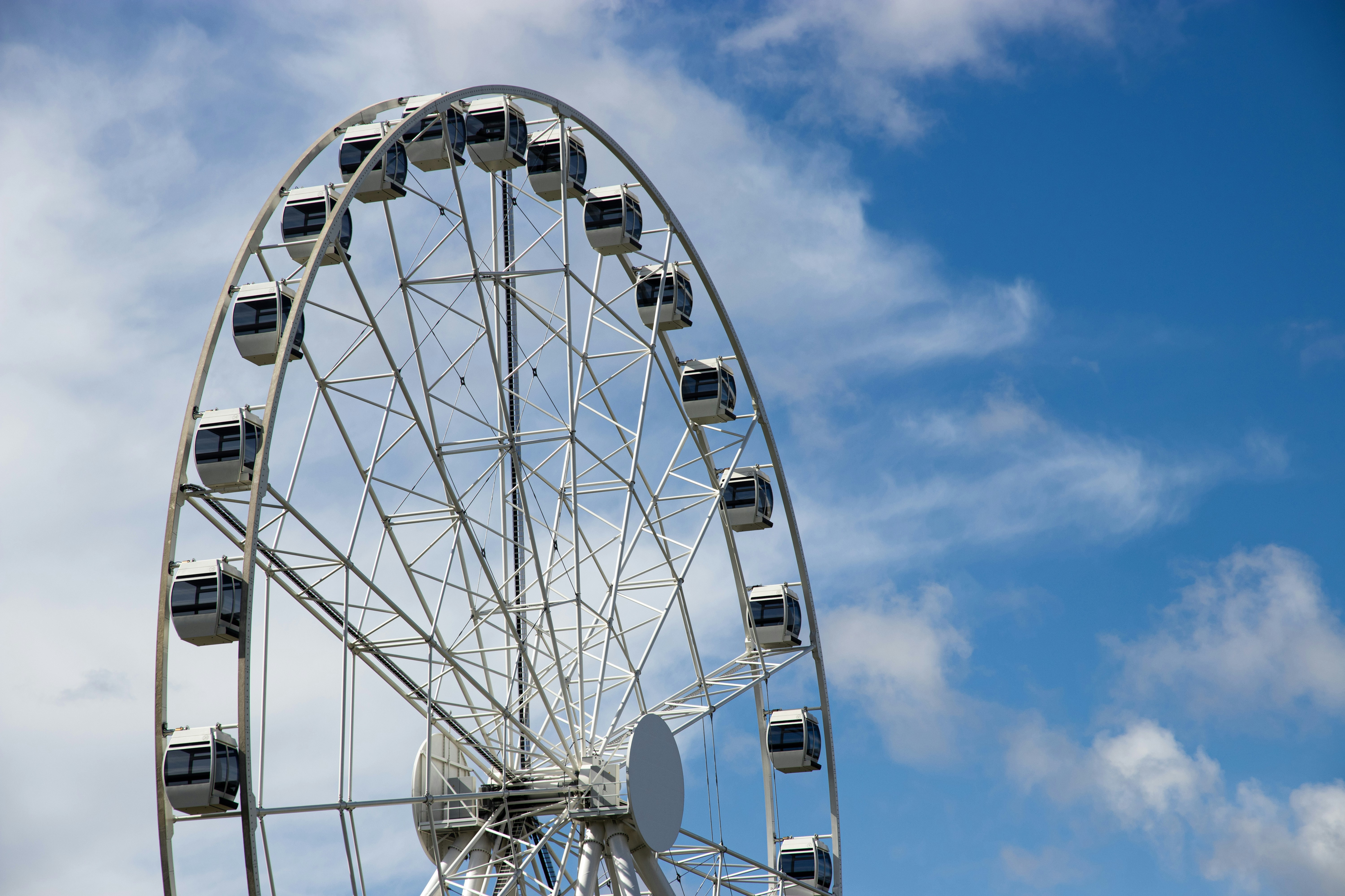A white ferris wheel against a blue sky.