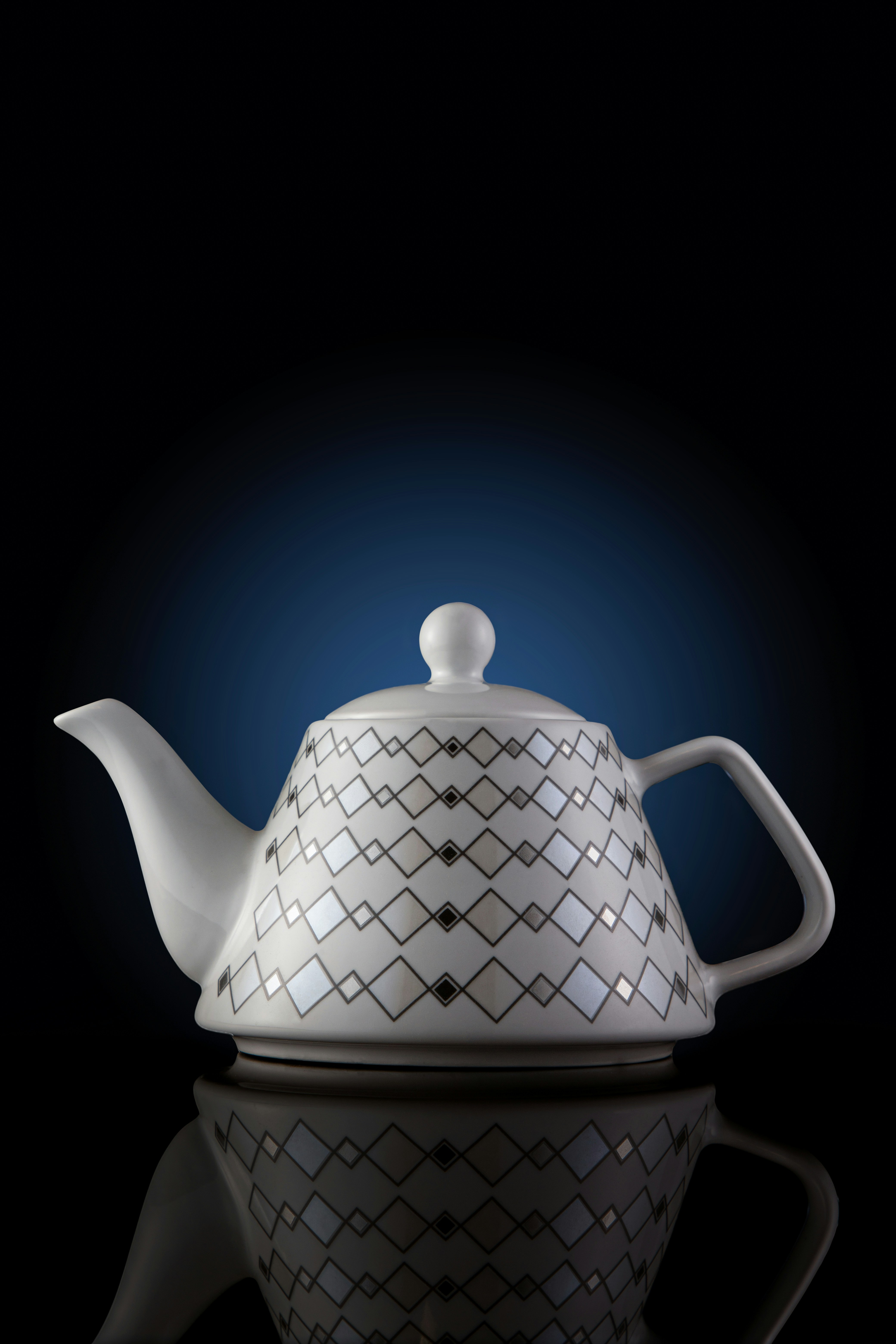 Tea is quiet wisdom in a cup | White teapot with geometric pattern on dark background