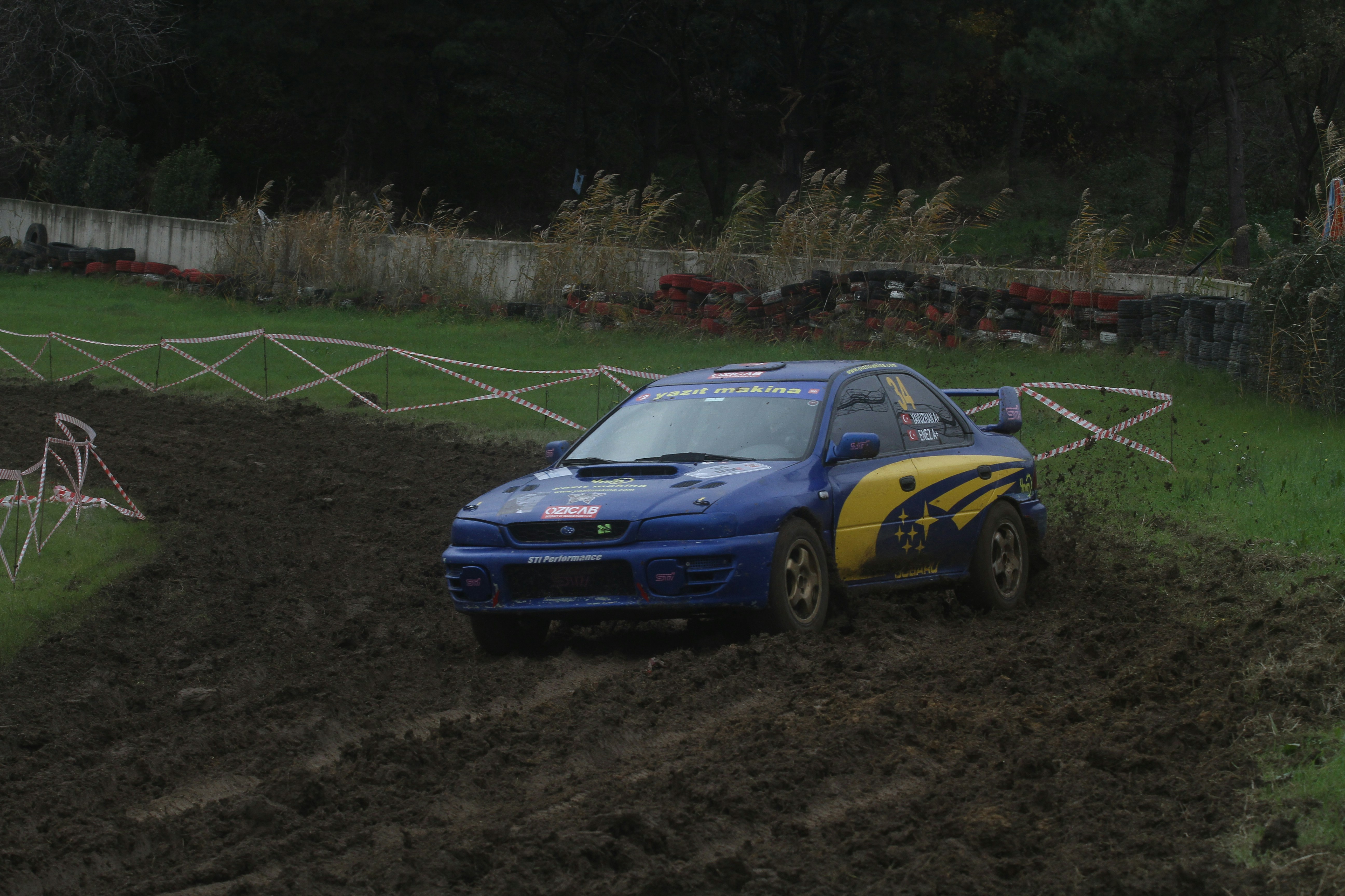 Blue rally car driving on a muddy track