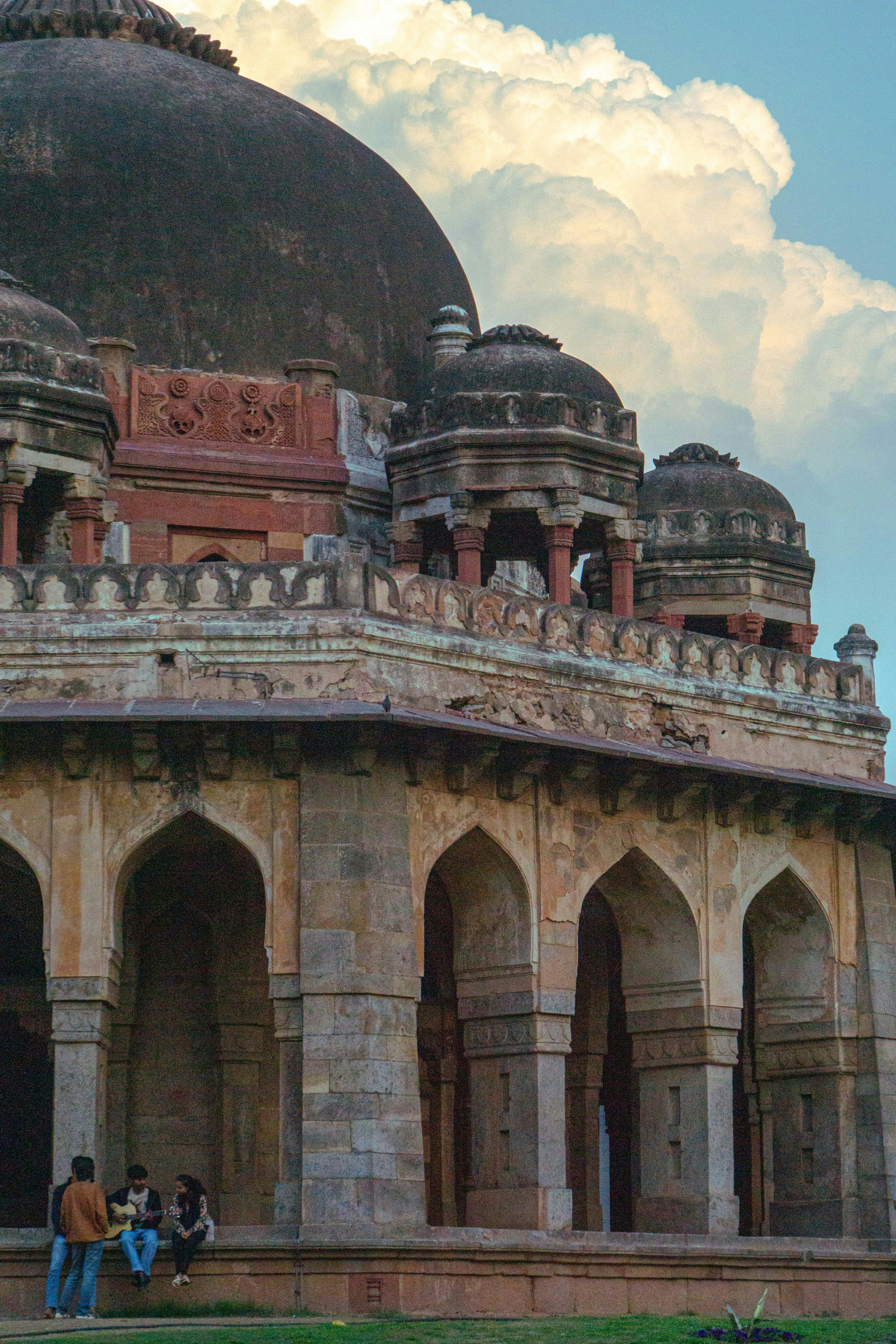 Ancient indian architecture with people sitting nearby.