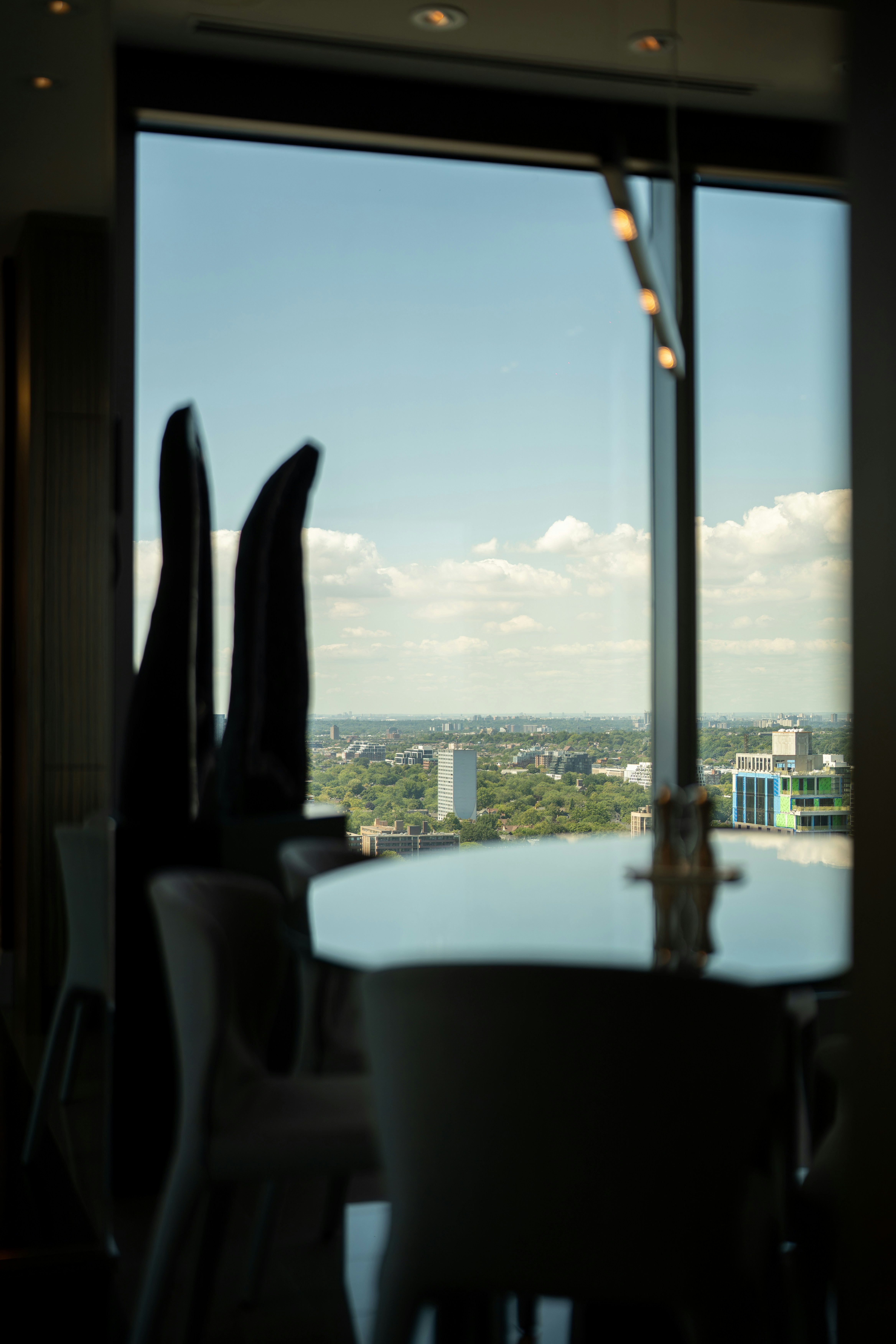 View from a modern high-rise showcasing a vibrant cityscape framed by sleek interior design elements. The interplay of light and space enhances the urban atmosphere.