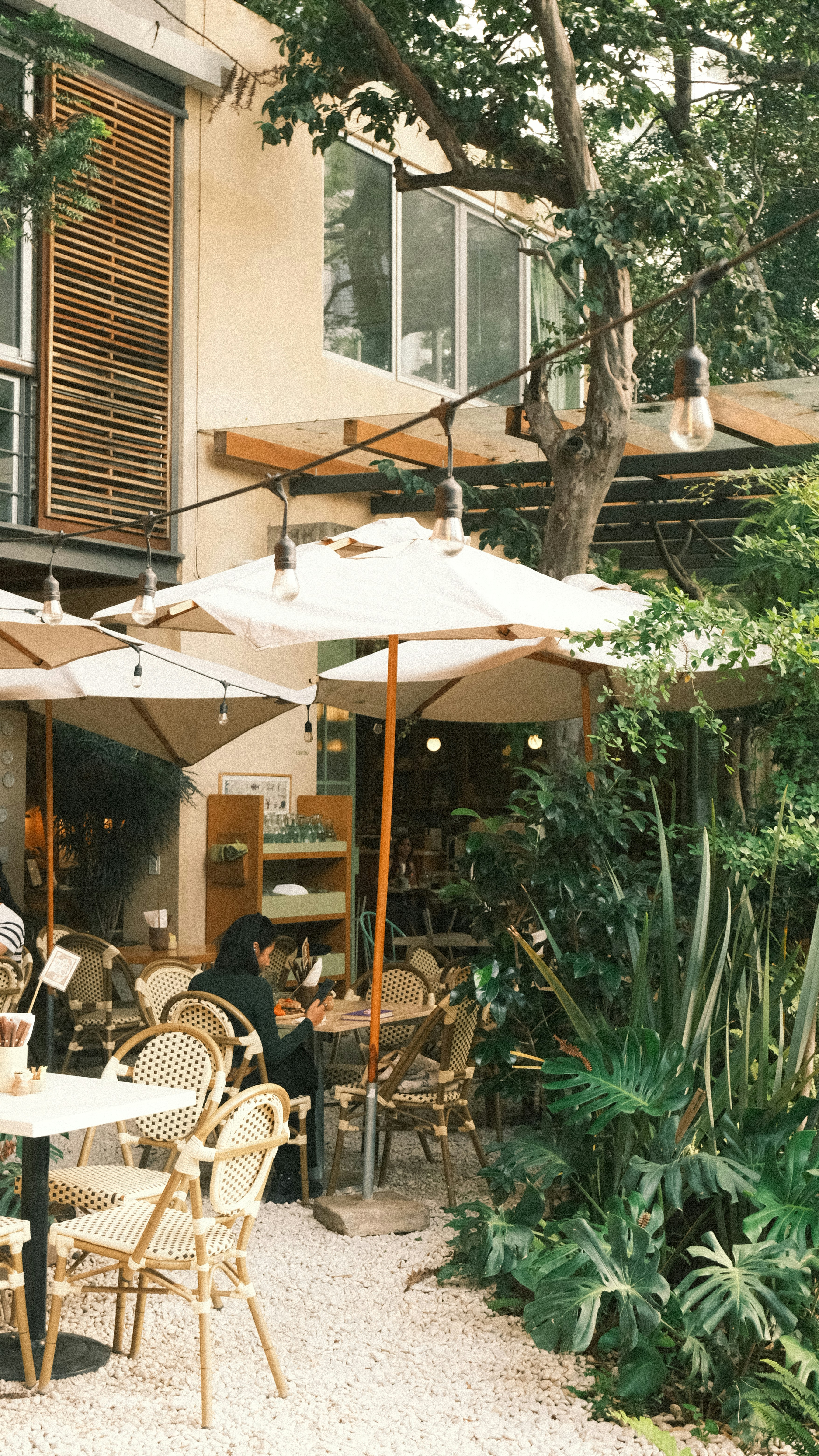People dining at outdoor cafe tables under umbrellas.