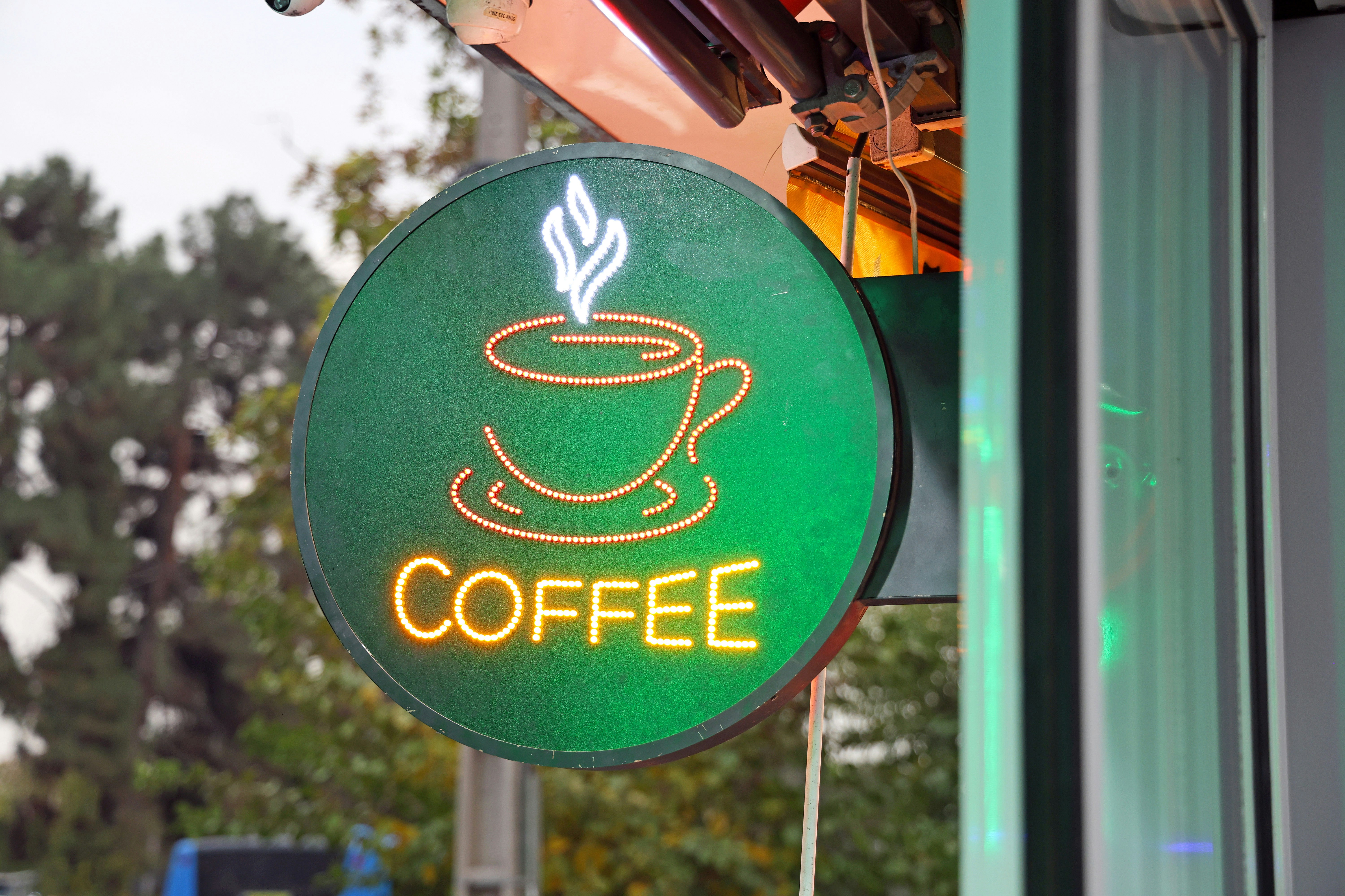 Green circular sign with "coffee" and steaming cup.