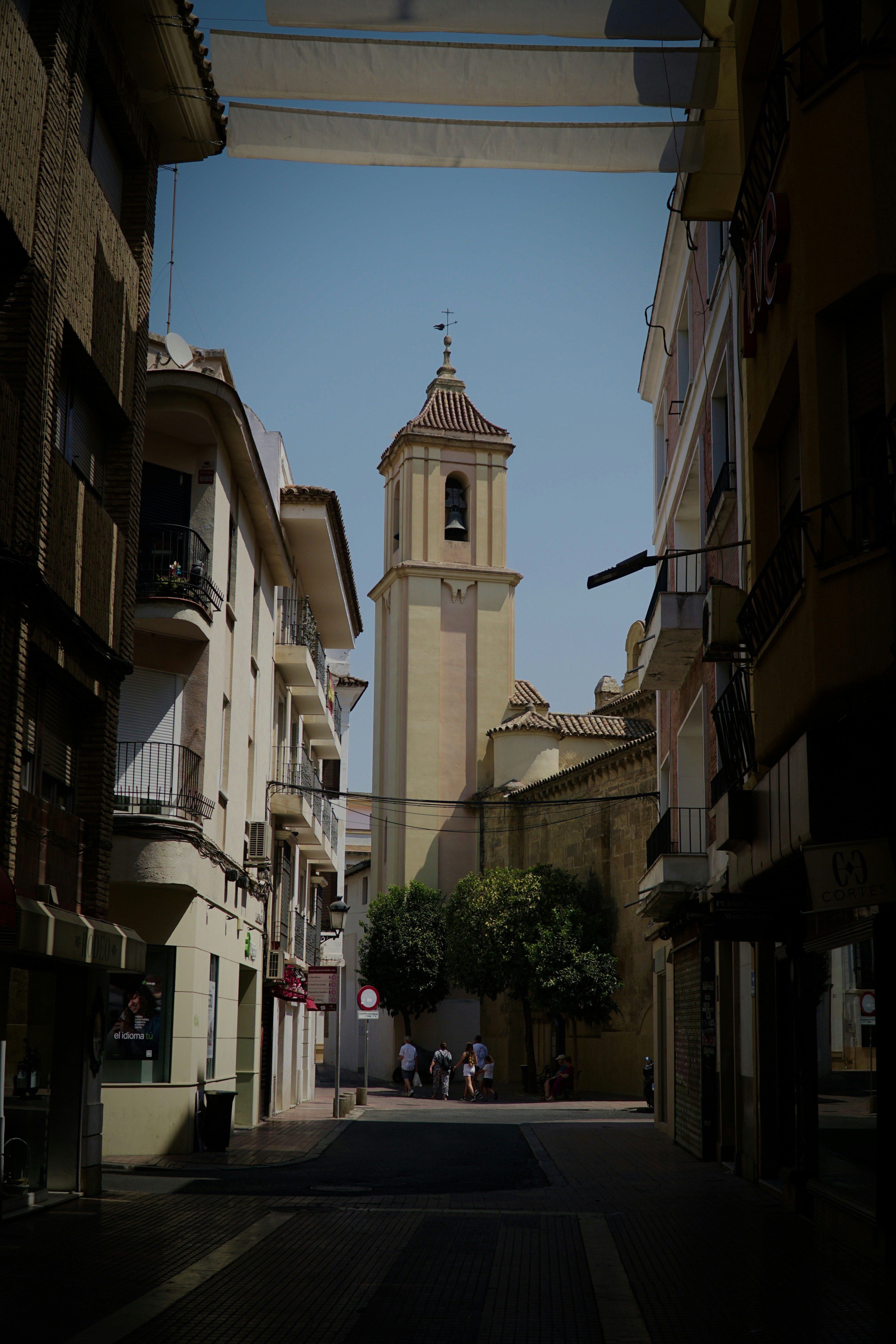 Bell tower of a church viewed from a narrow street.