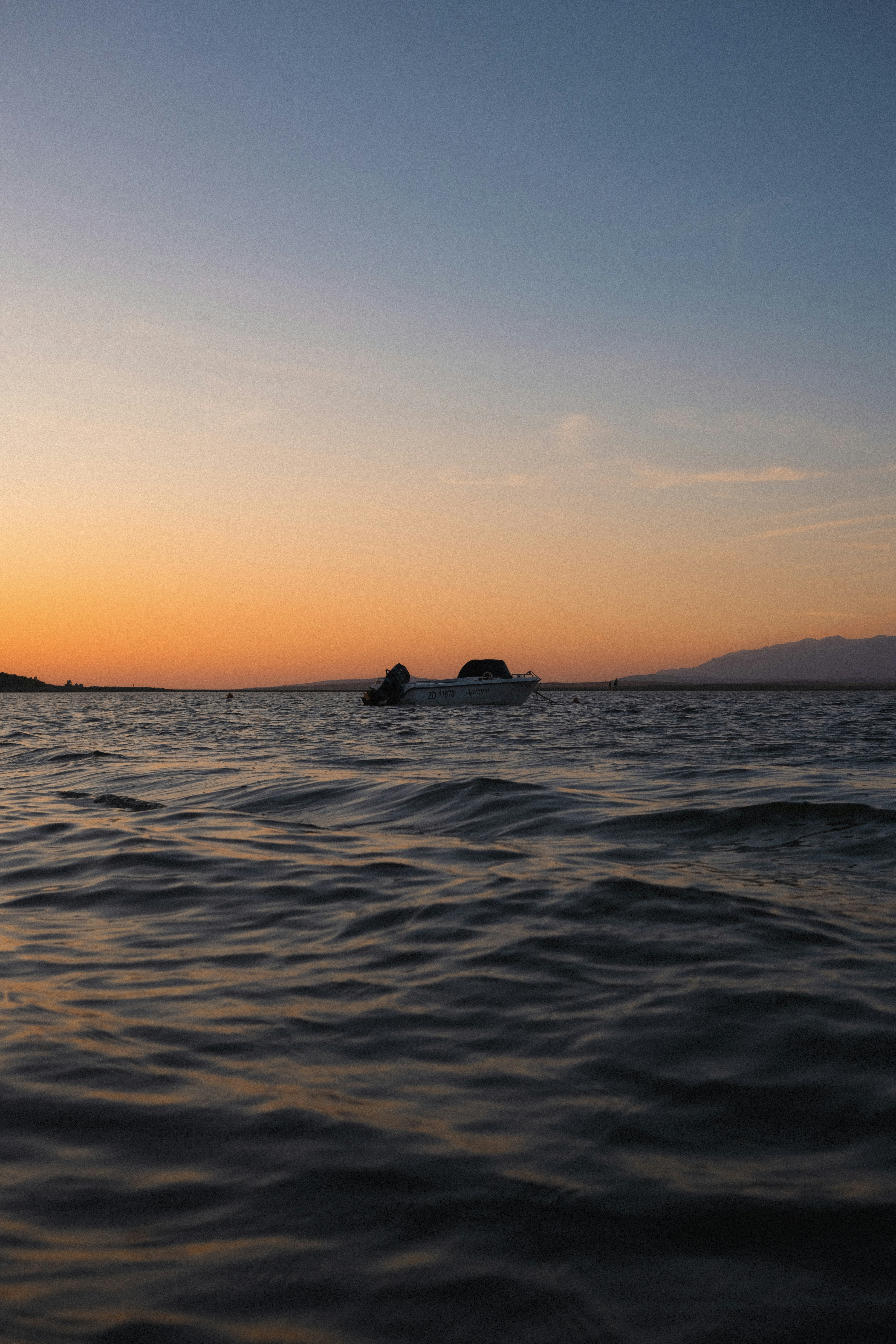Boat on calm water at sunset with mountains