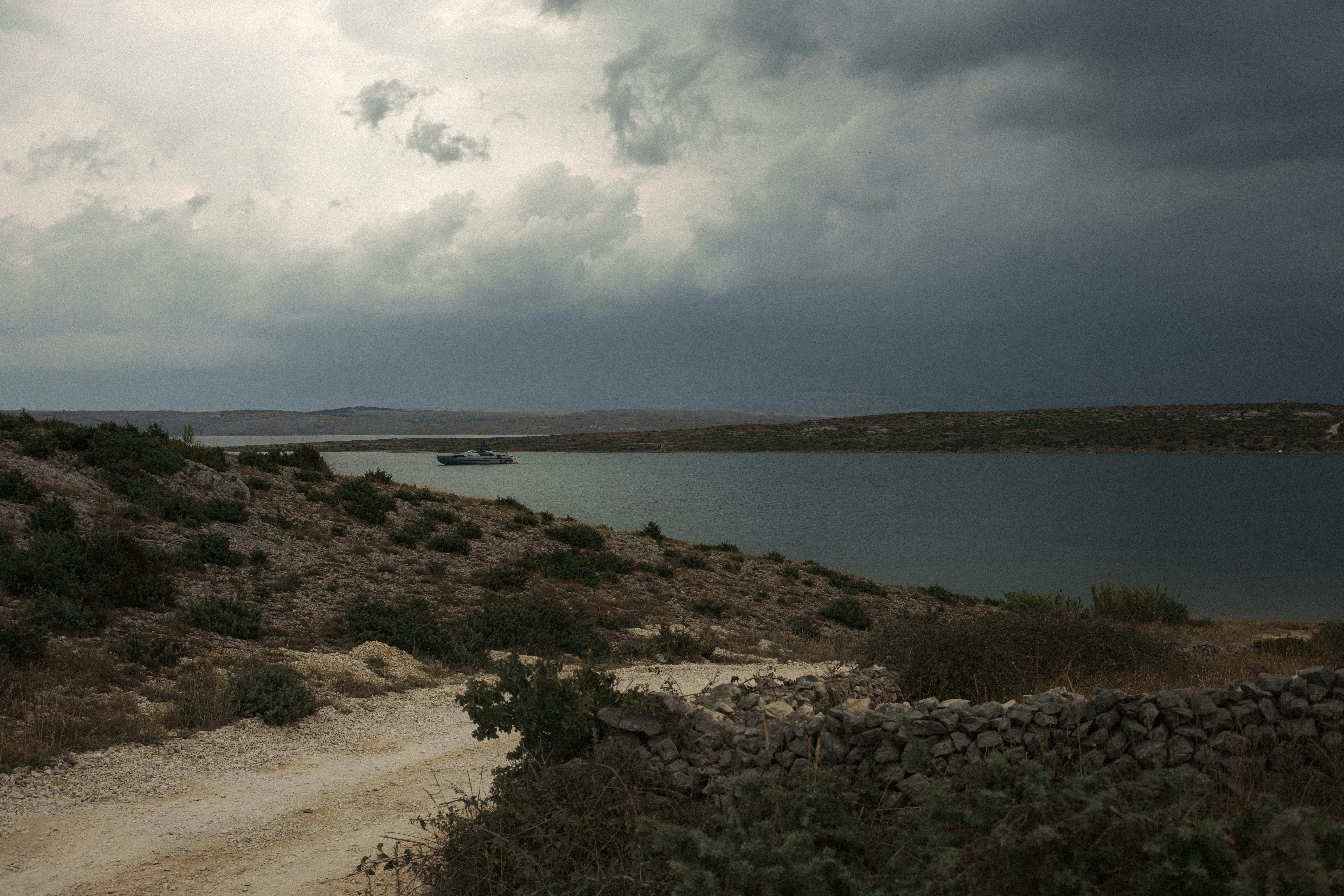 Rocky shore with a boat on the water under clouds