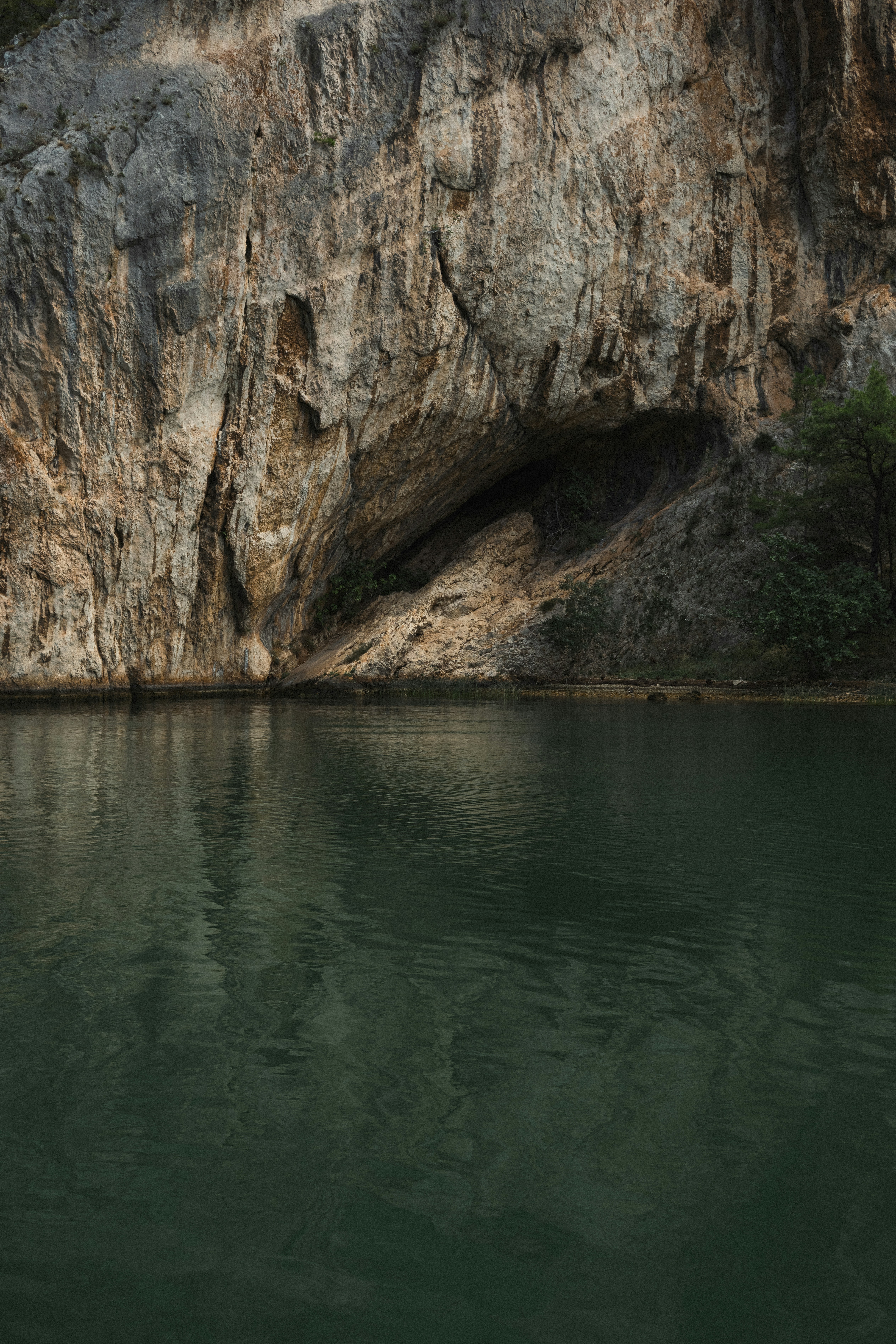 Cave entrance in a rocky cliff above green water
