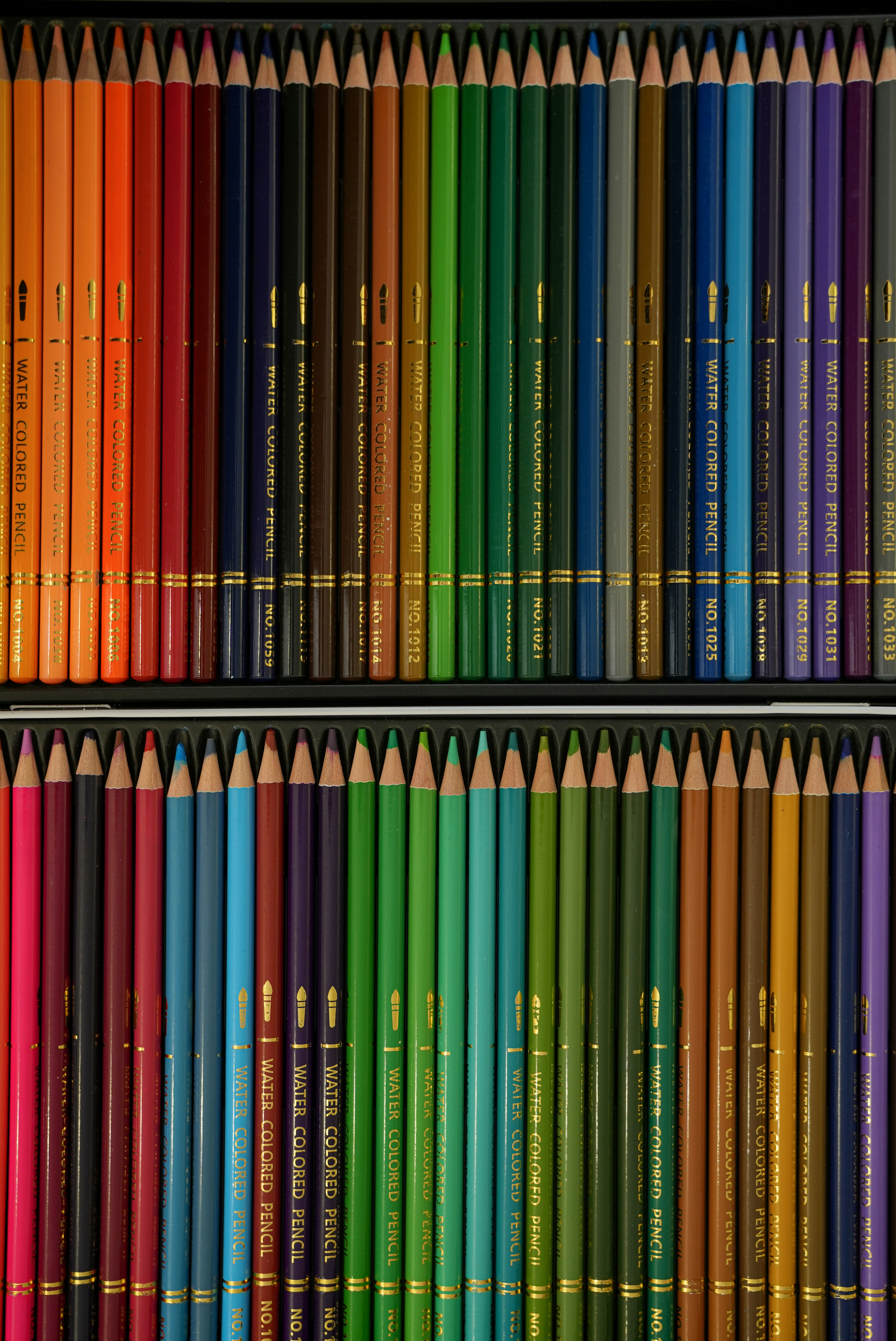 Colored pencils arranged side by side | Two rows of colored pencils neatly arranged.