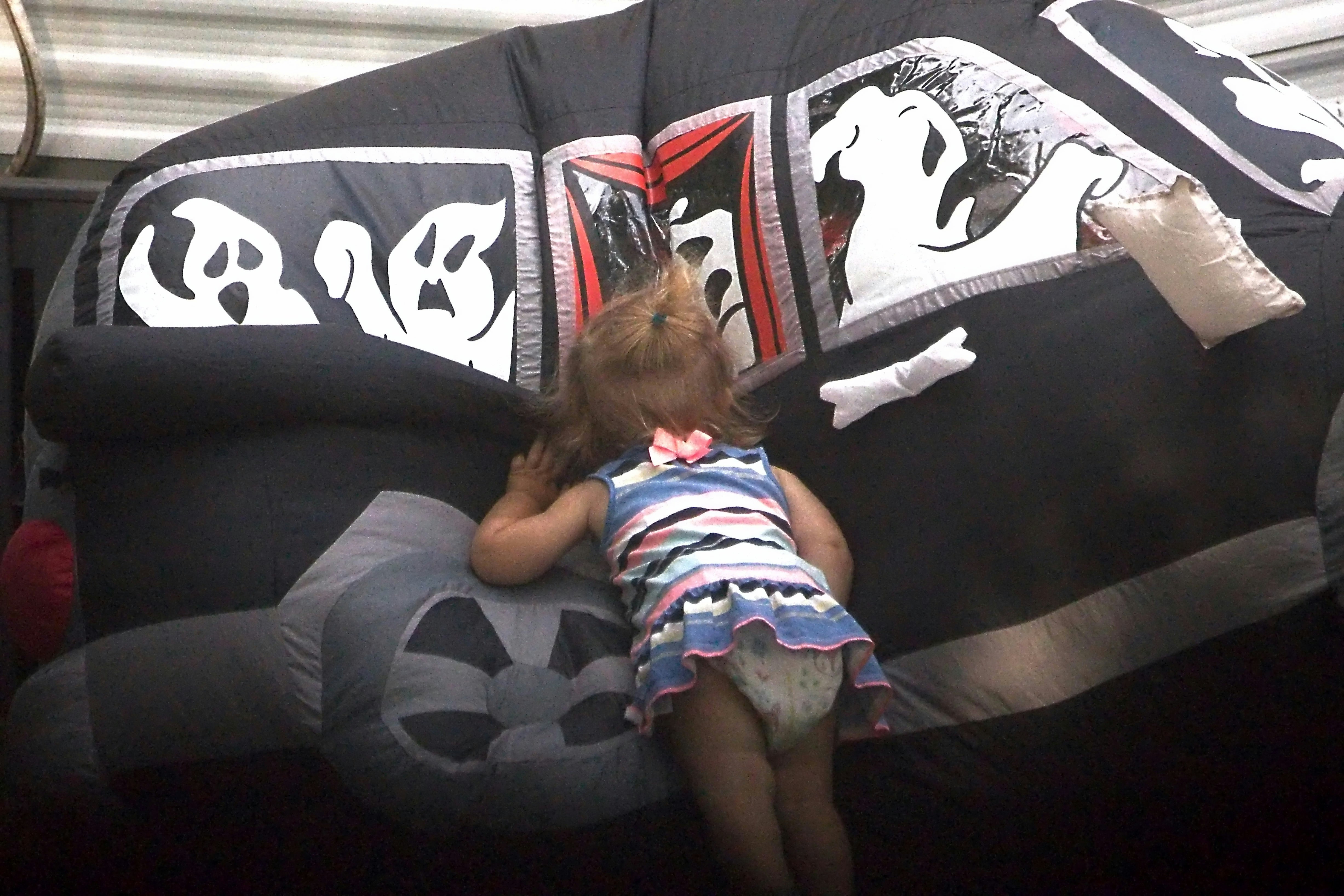 Toddler peeking into a halloween inflatable decoration.