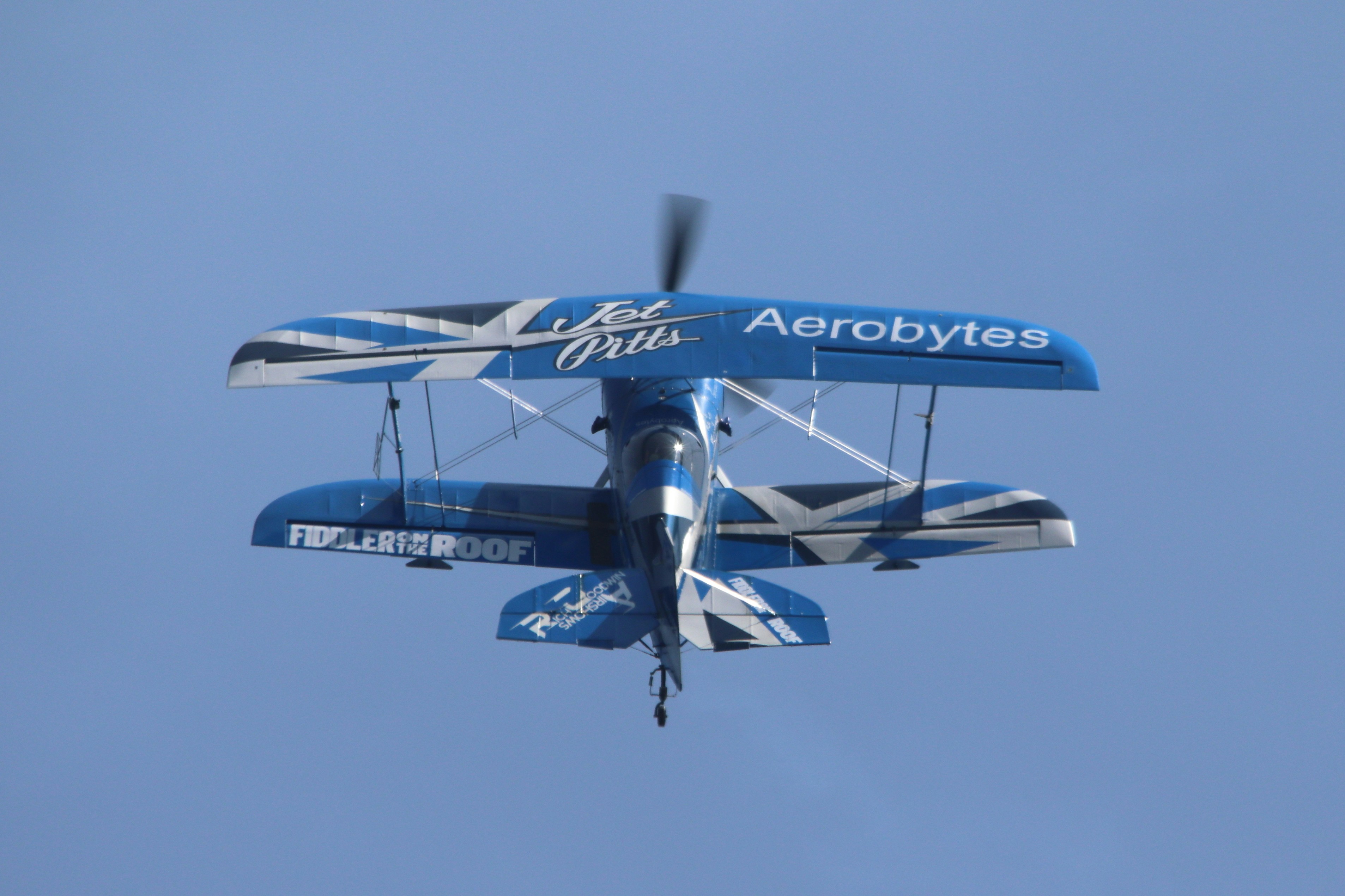 Blue biplane flying against a clear sky